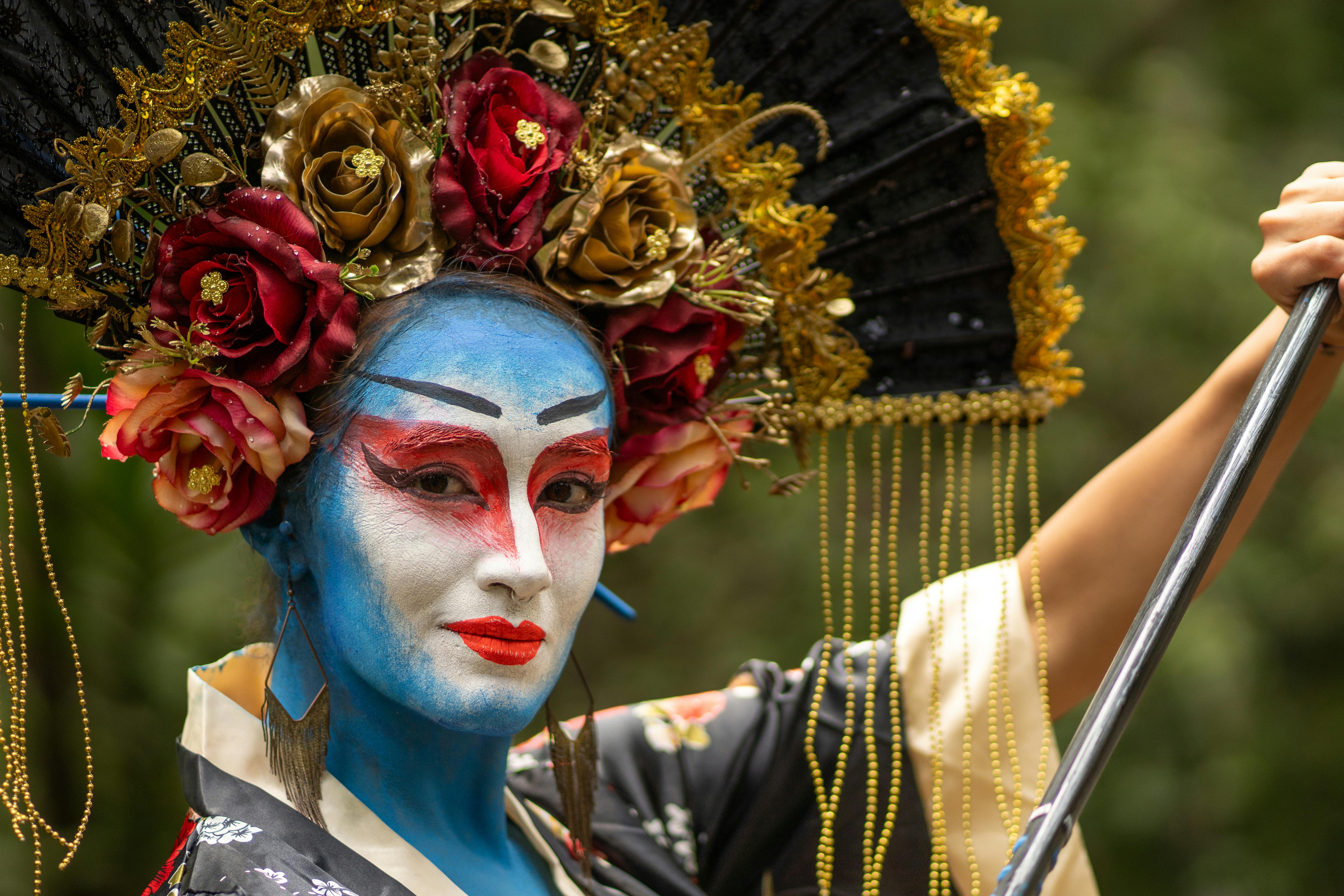 A woman with blue face paint and a fan · Free Stock Photo