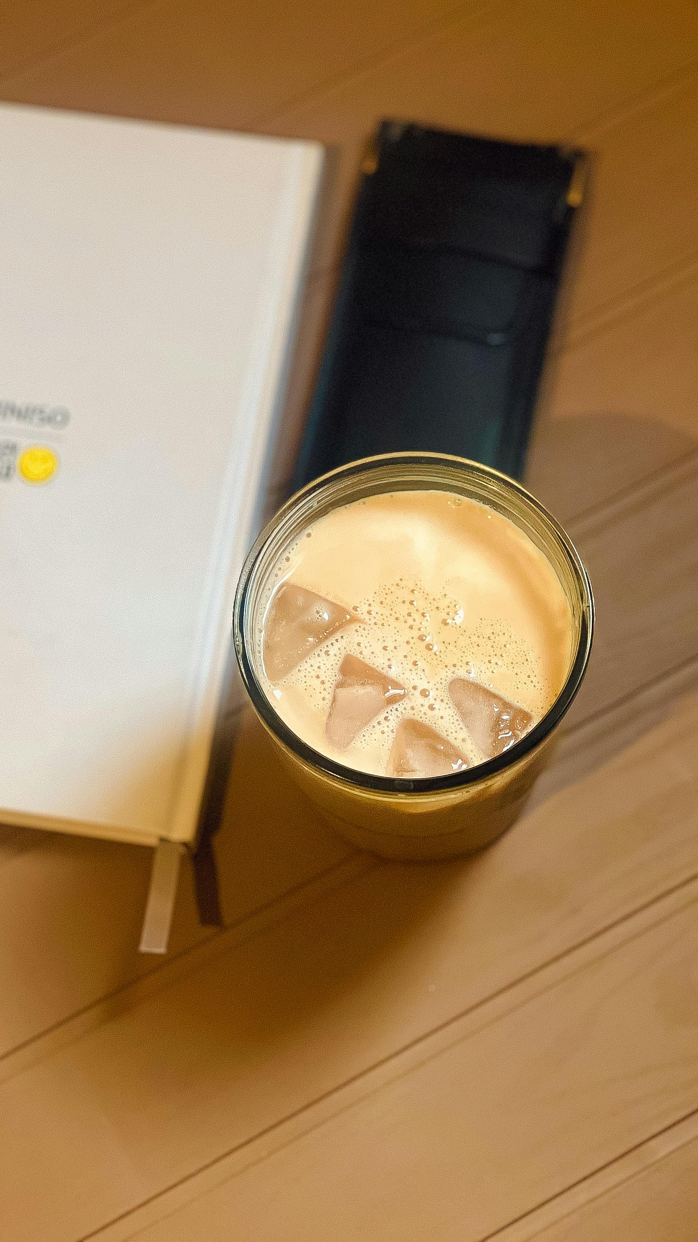 A Cup of Iced Coffee Standing next to a Notebook · Free Stock Photo