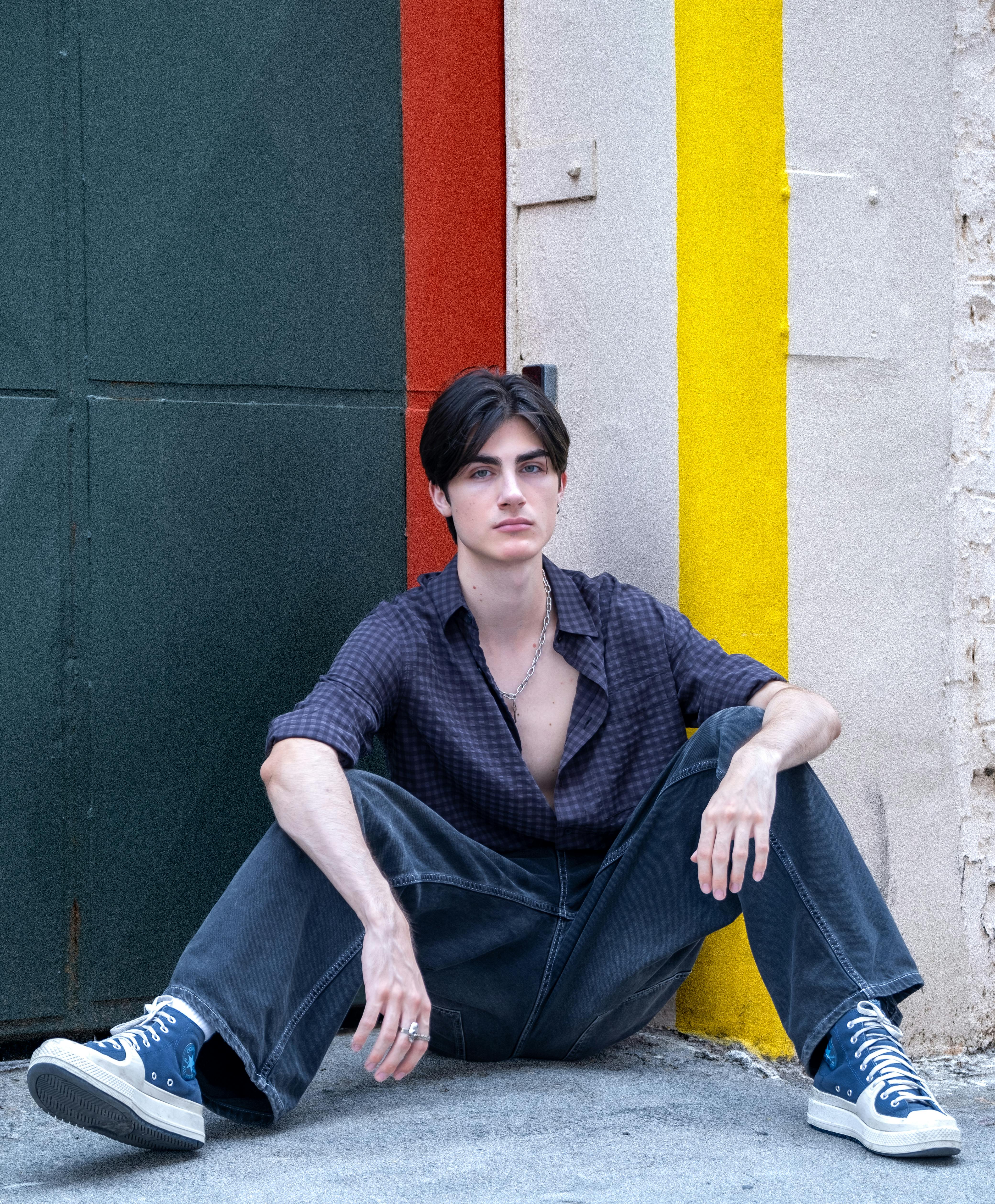 Urban Male Model Sitting Against Colorful Wall in Street Style Fashion ...