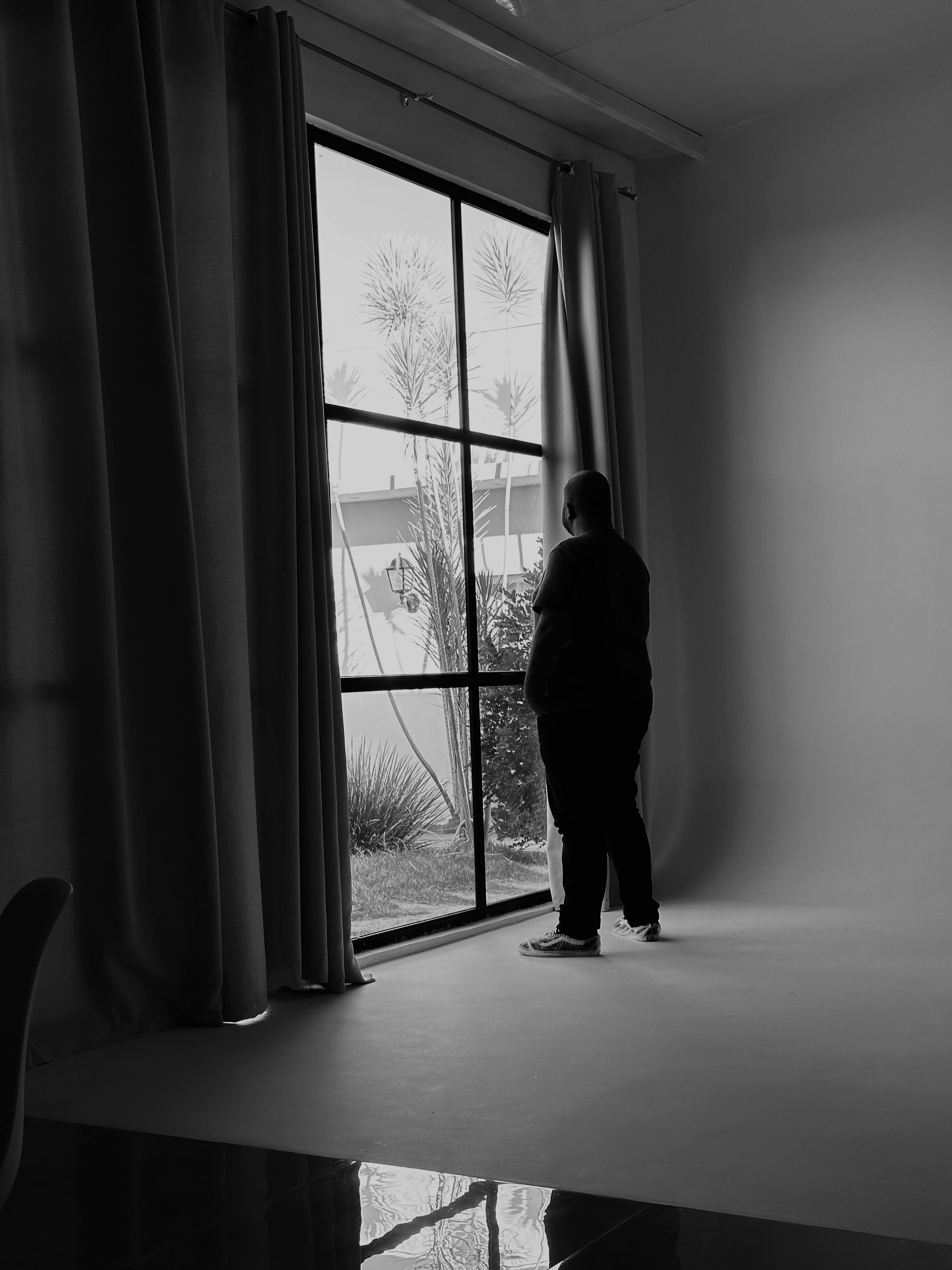 Man Standing near Windows in Black and White · Free Stock Photo
