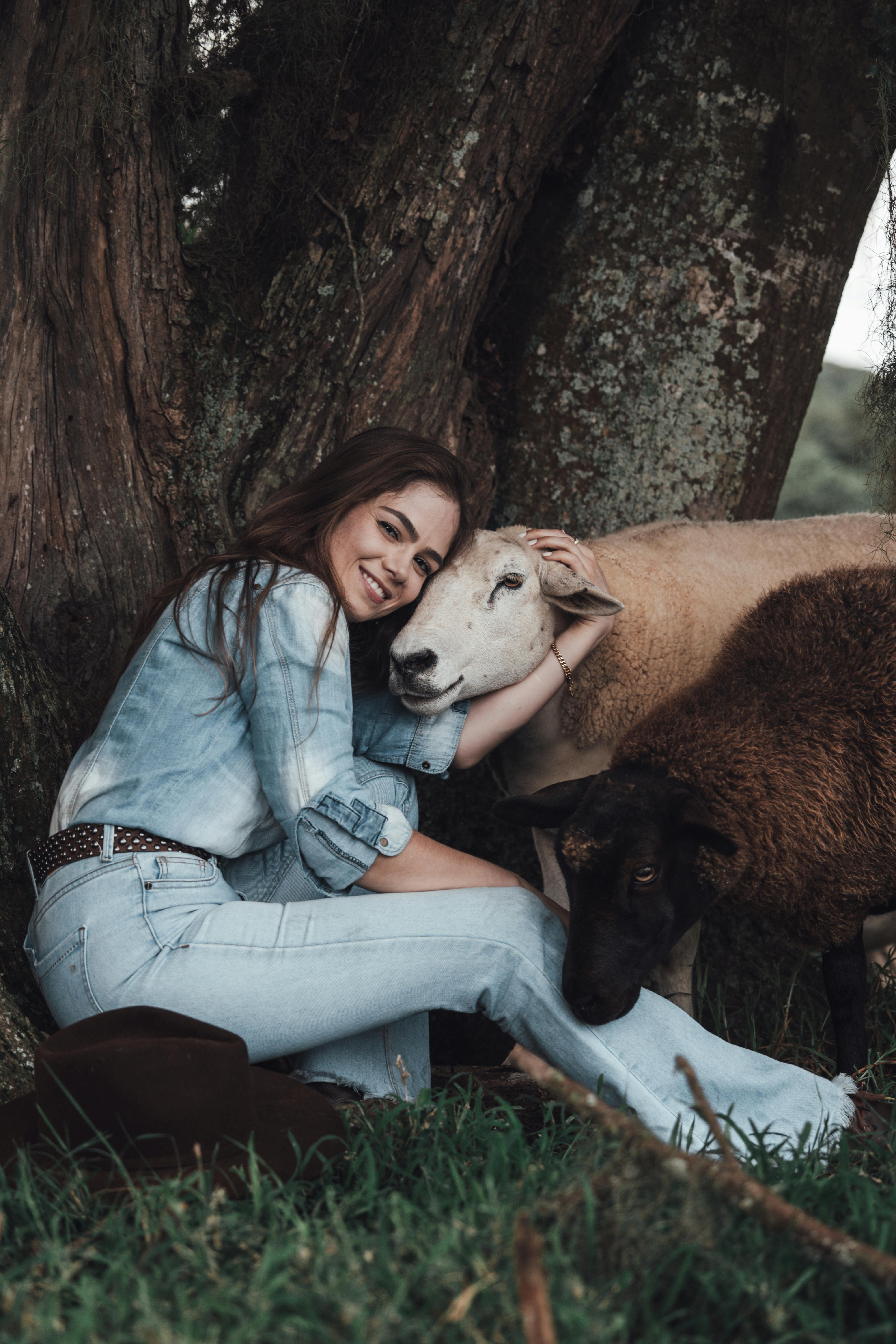 Smiling Woman Sitting and Hugging Sheep · Free Stock Photo