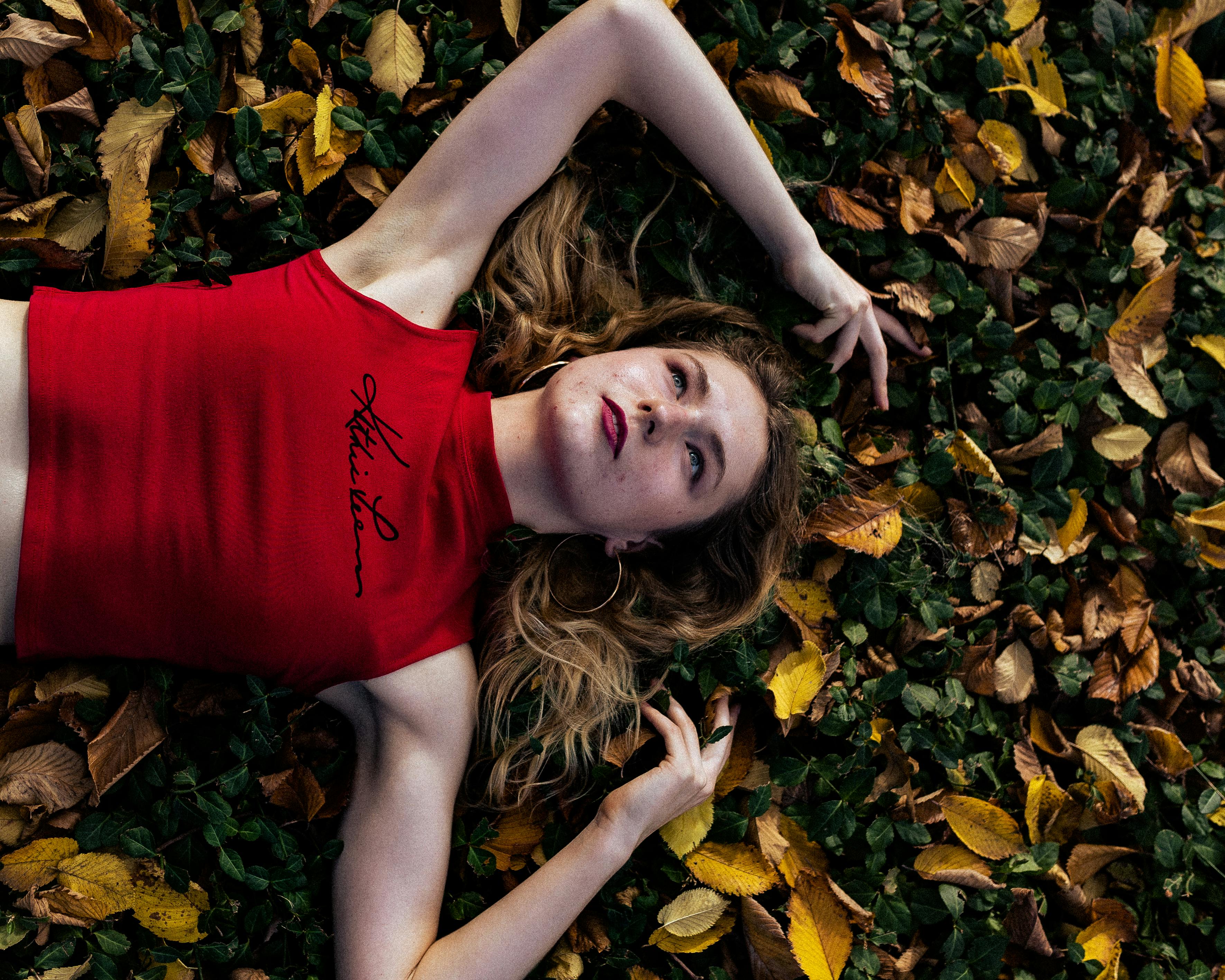 Woman in Tank Top Lying Down on Ground in Autumn · Free Stock Photo