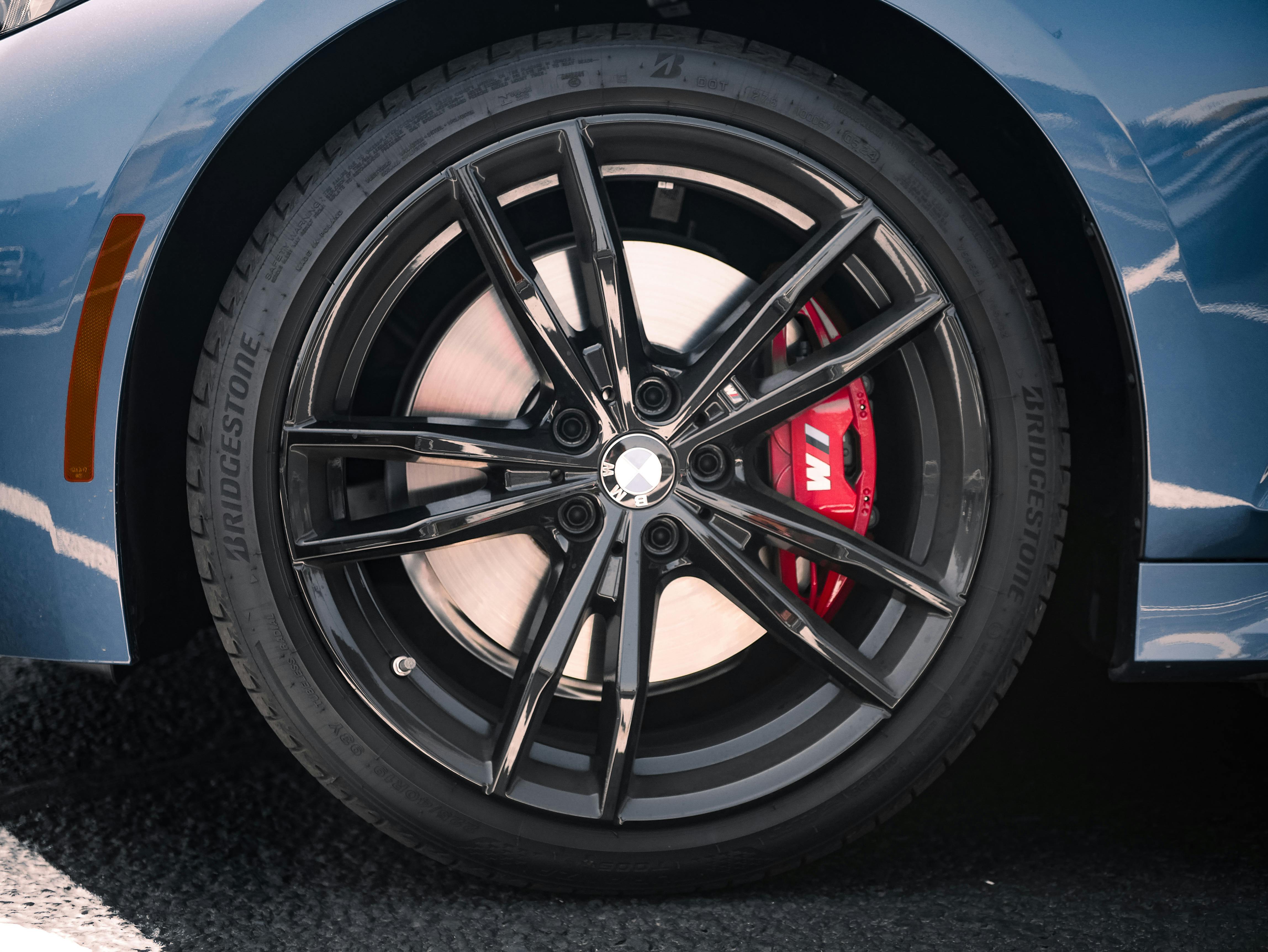 The front wheel of a blue car with red brake calipers · Free Stock Photo