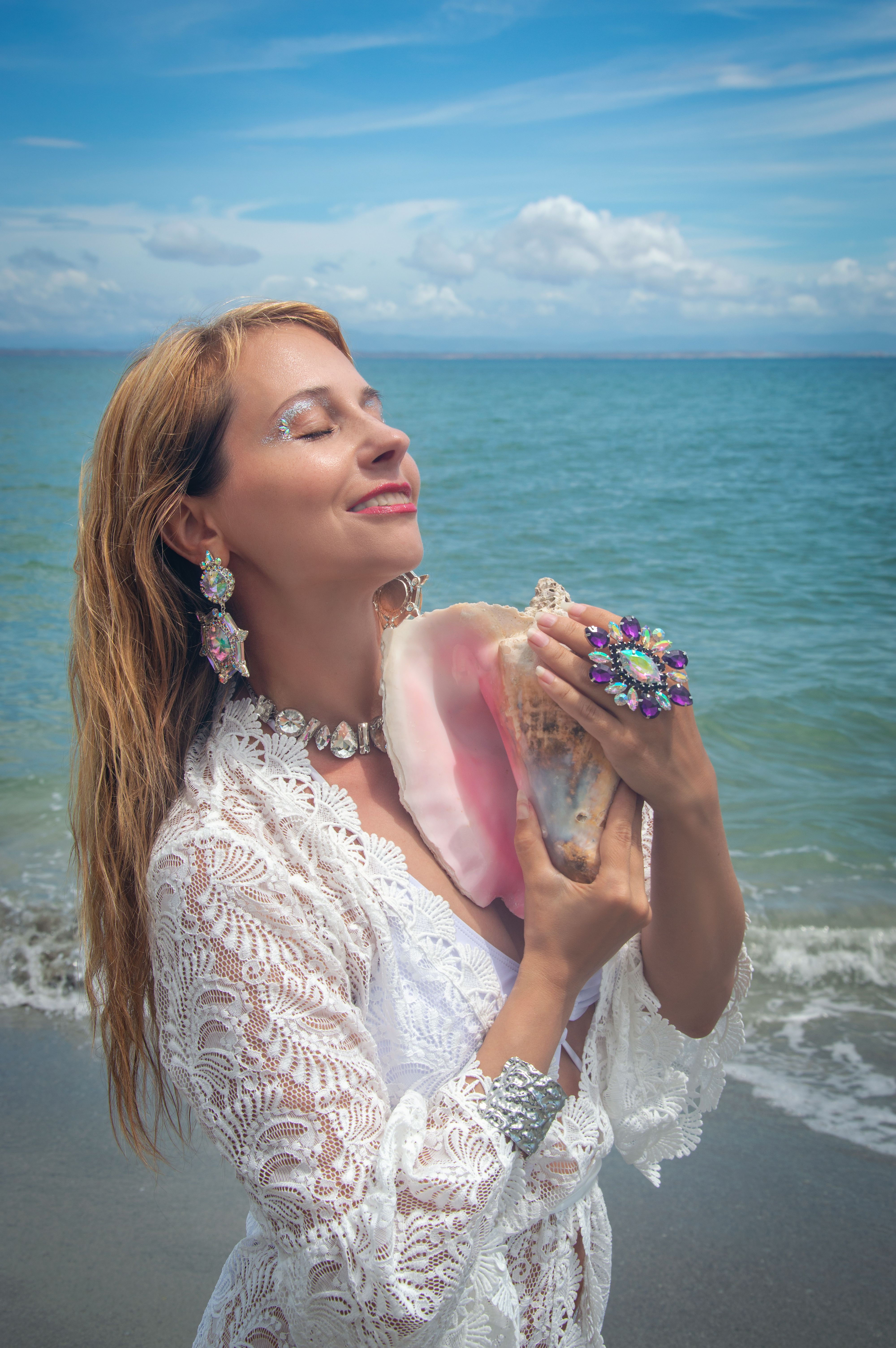 Portrait of Smiling Woman Holding Shell on Sea Shore · Free Stock Photo