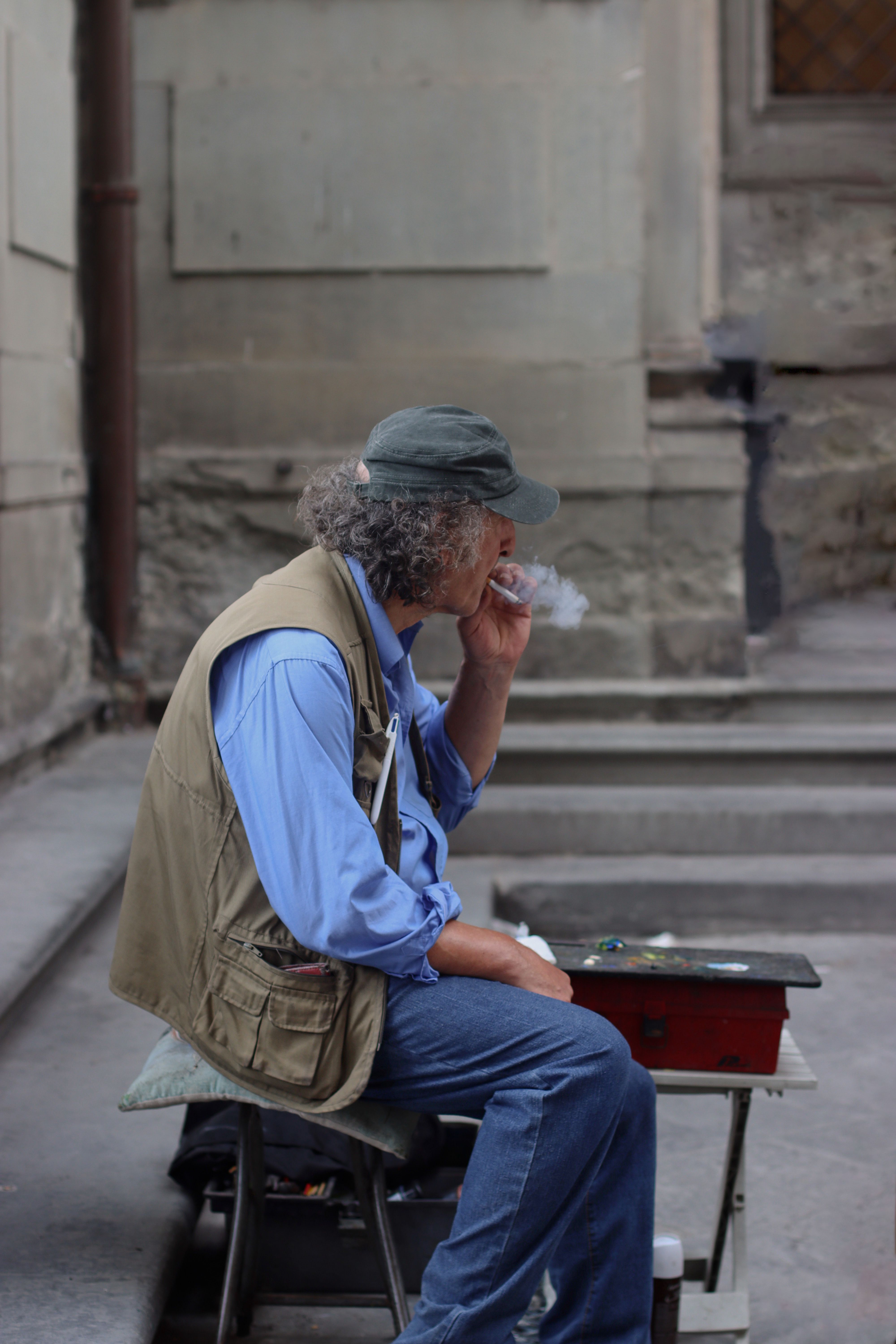 A man sitting on a bench smoking a cigarette · Free Stock Photo