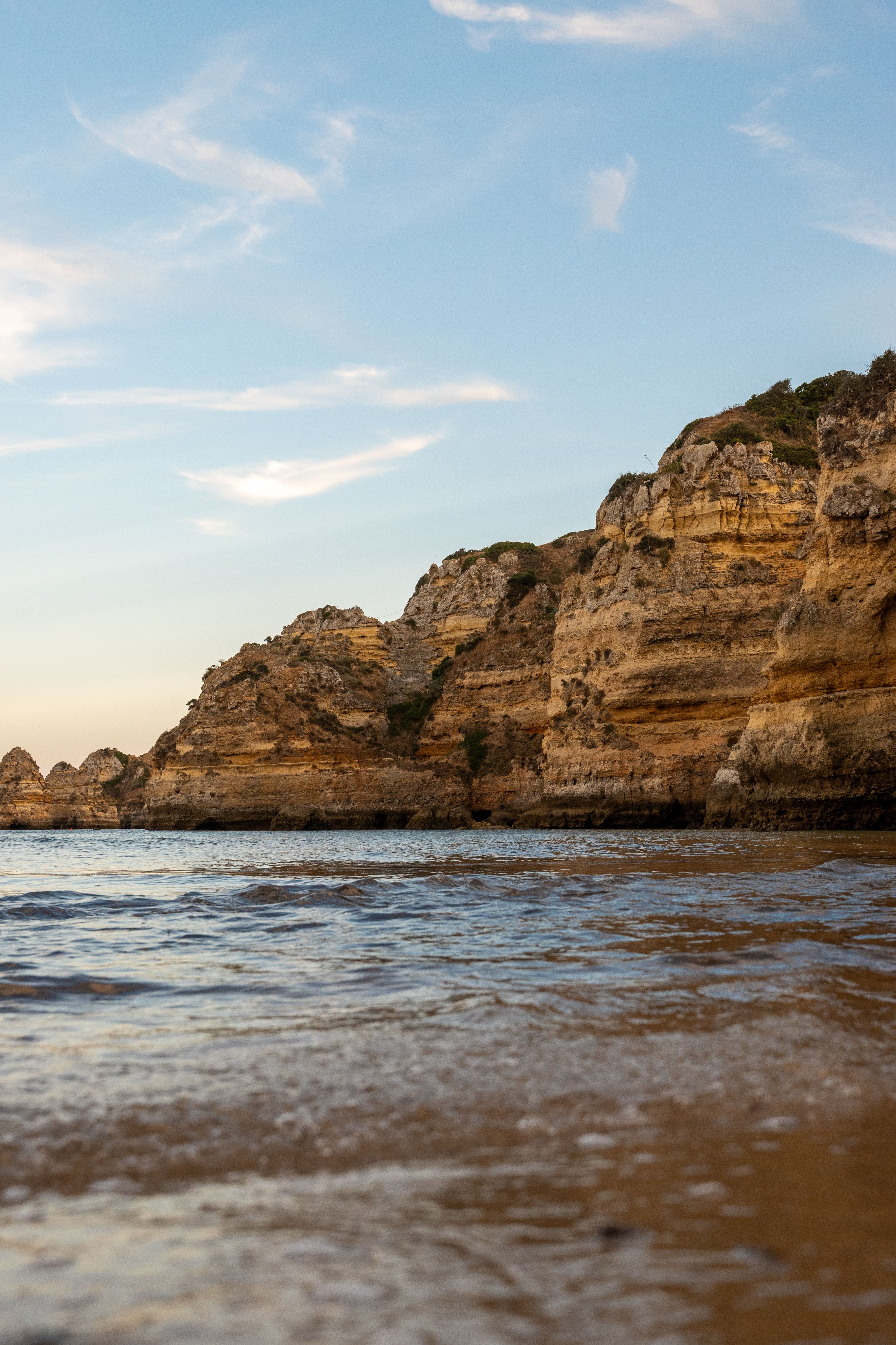 A beach with cliffs and water at sunset · Free Stock Photo