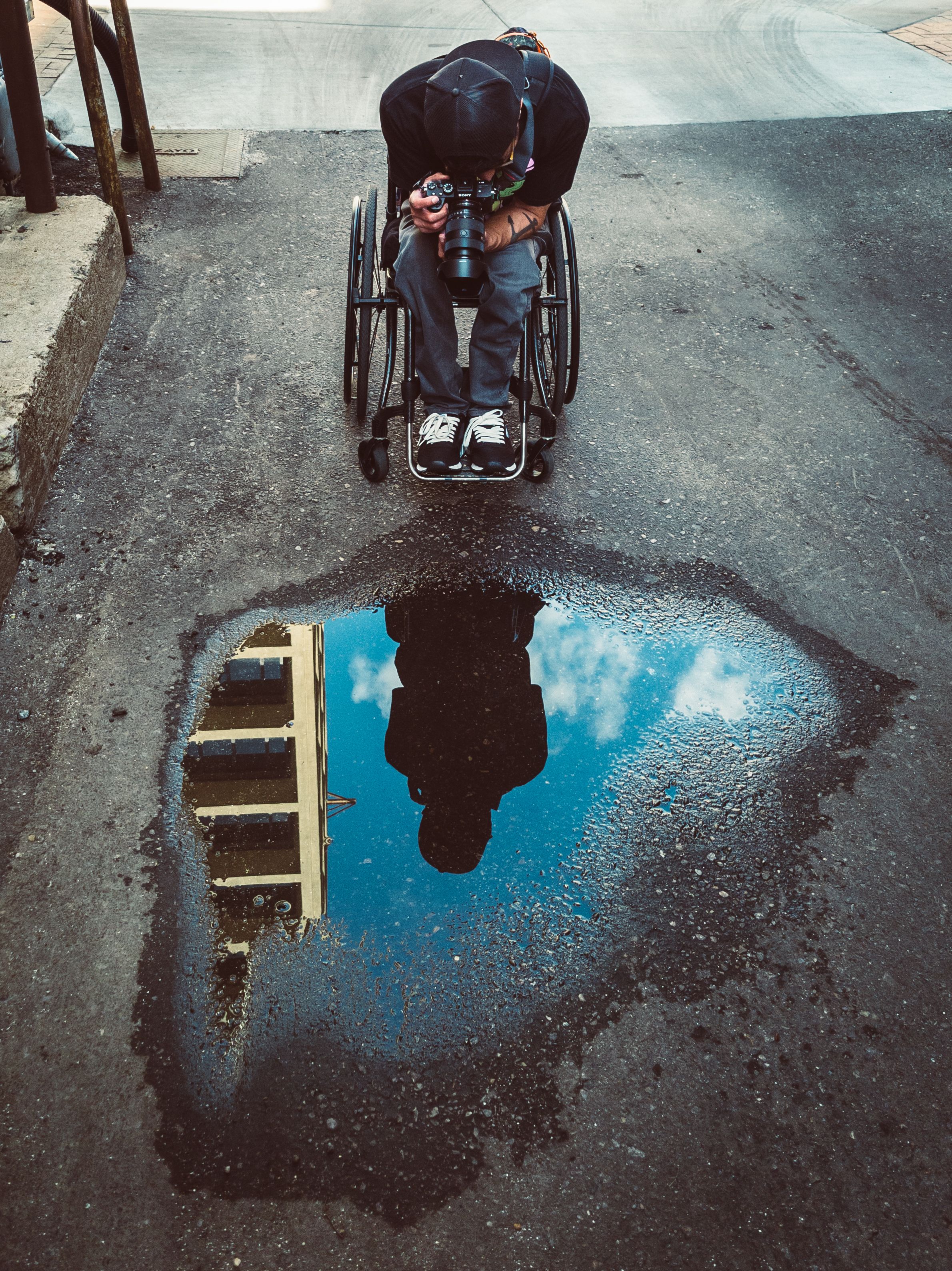 A man in a wheelchair looking at a puddle · Free Stock Photo