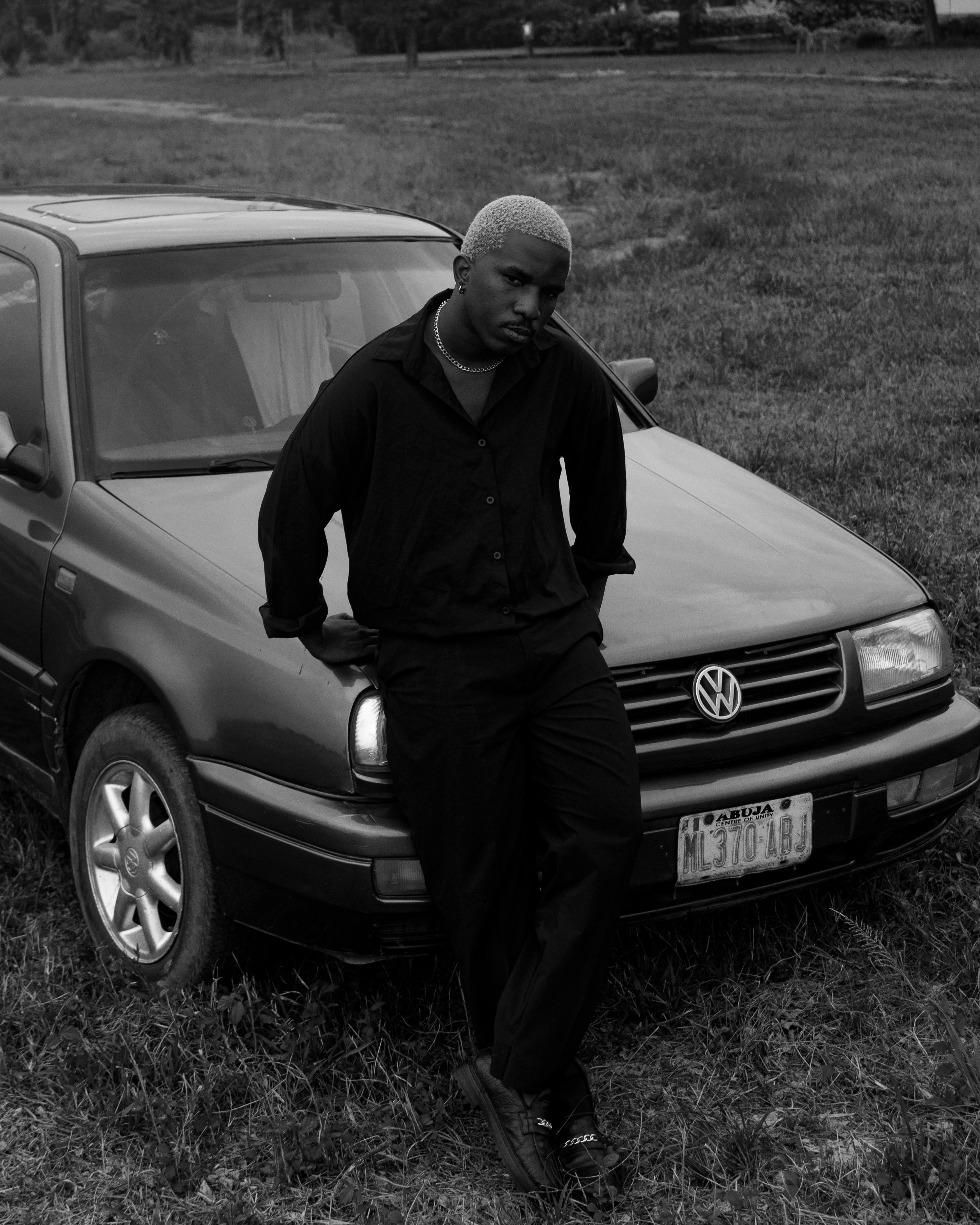 A man leaning against a car in a field · Free Stock Photo