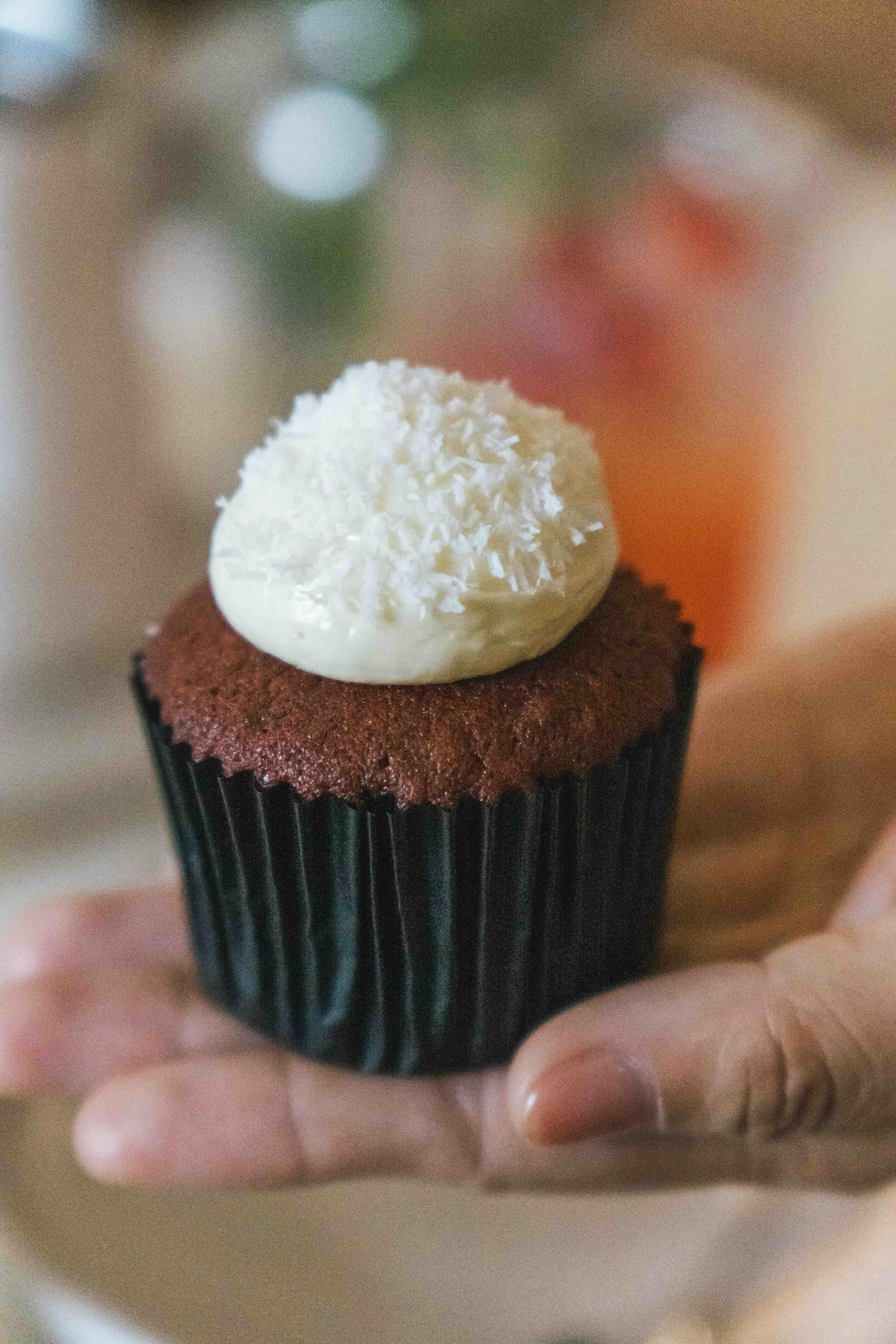 A person holding a cupcake with coconut frosting · Free Stock Photo
