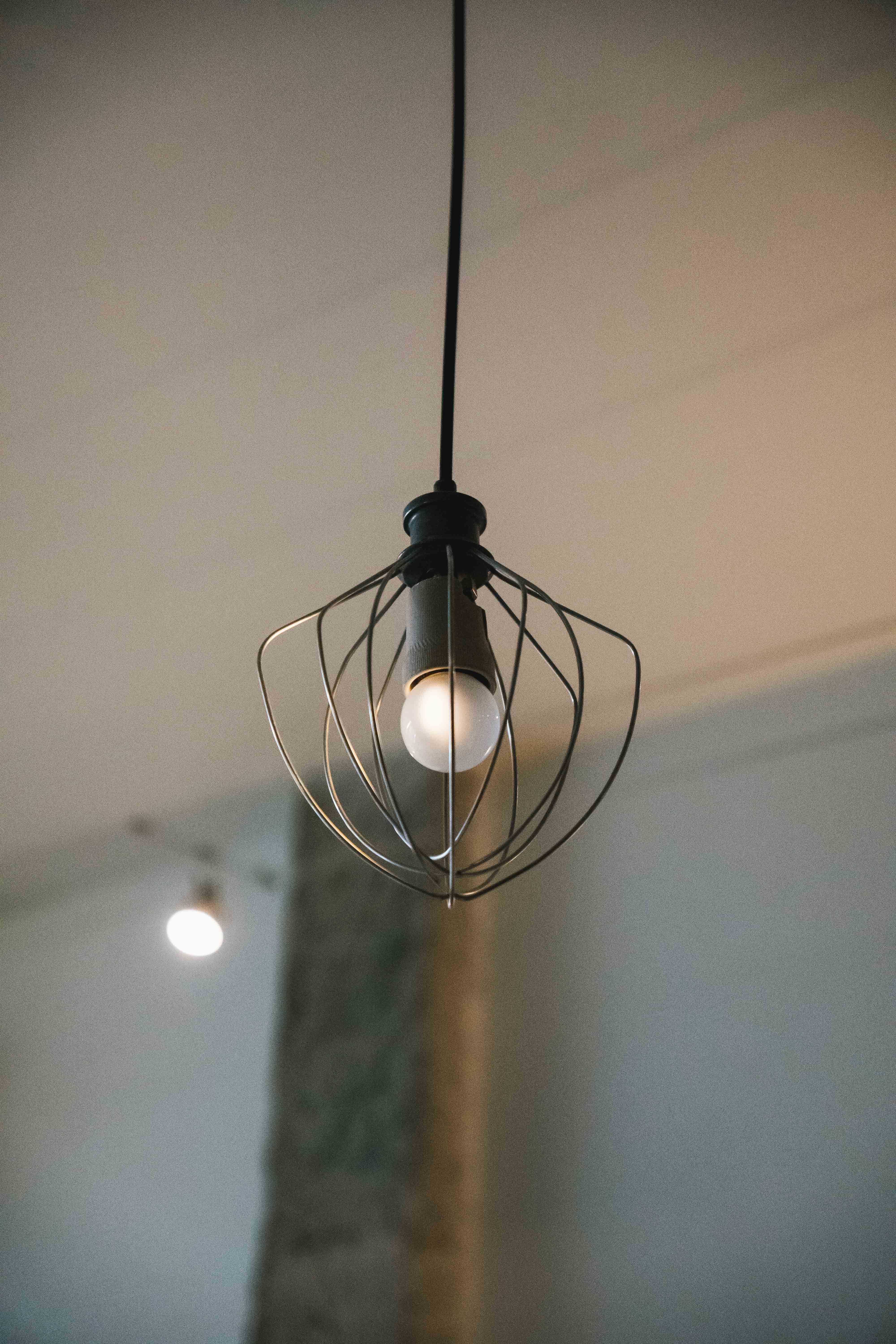 A light fixture with a wire cage hanging from it · Free Stock Photo
