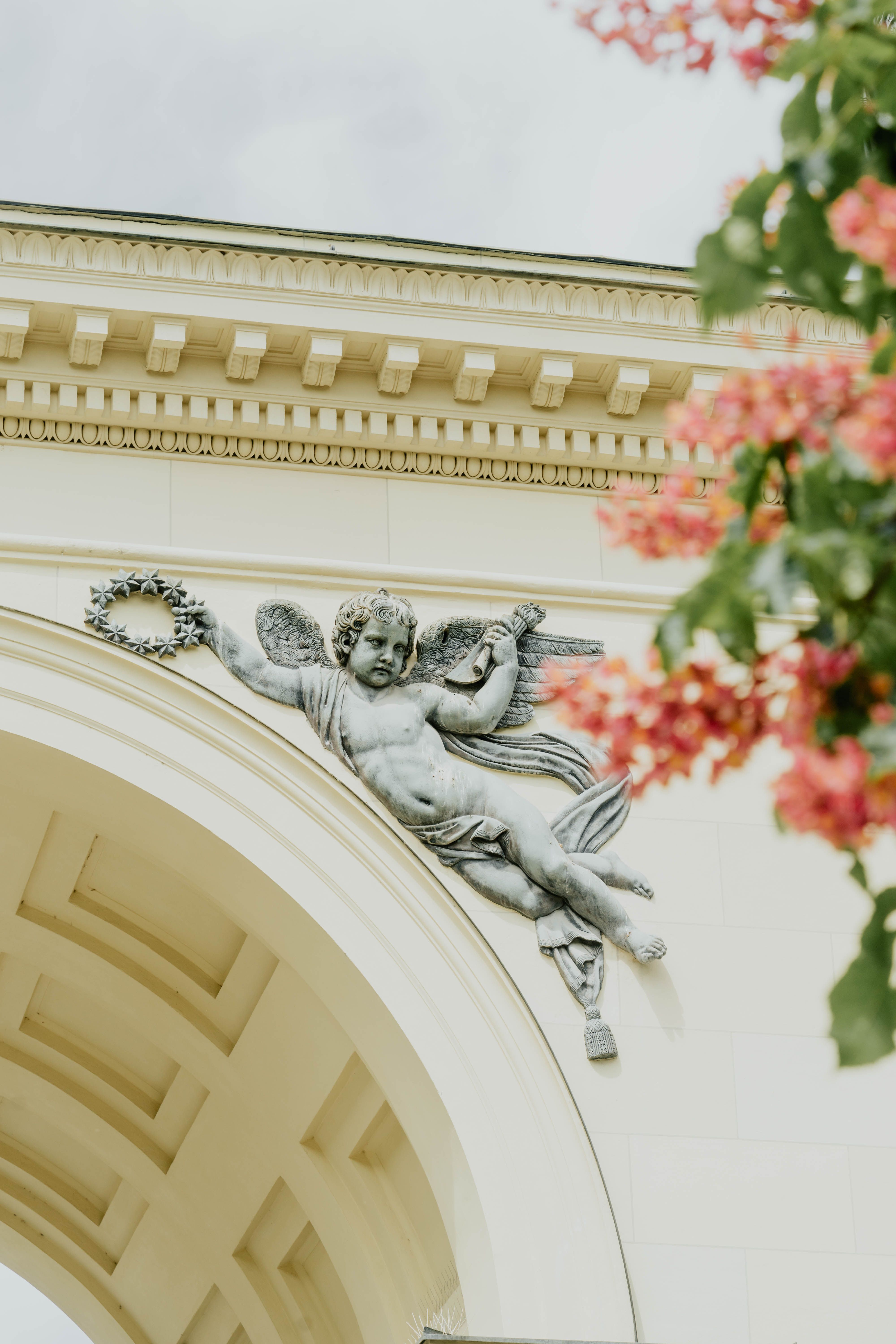 A statue is on the arch of a building · Free Stock Photo