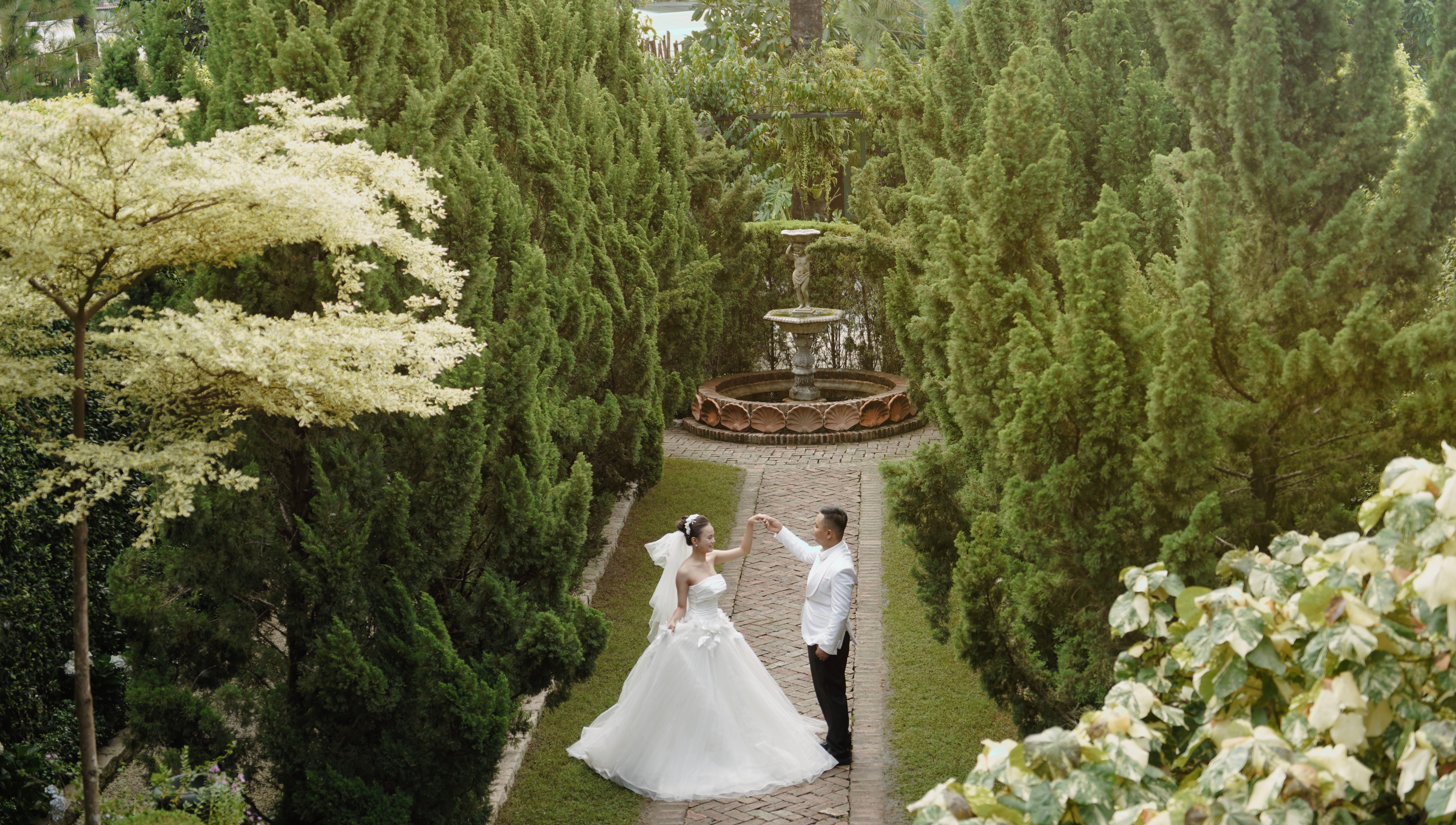 A bride and groom walking through a garden · Free Stock Photo