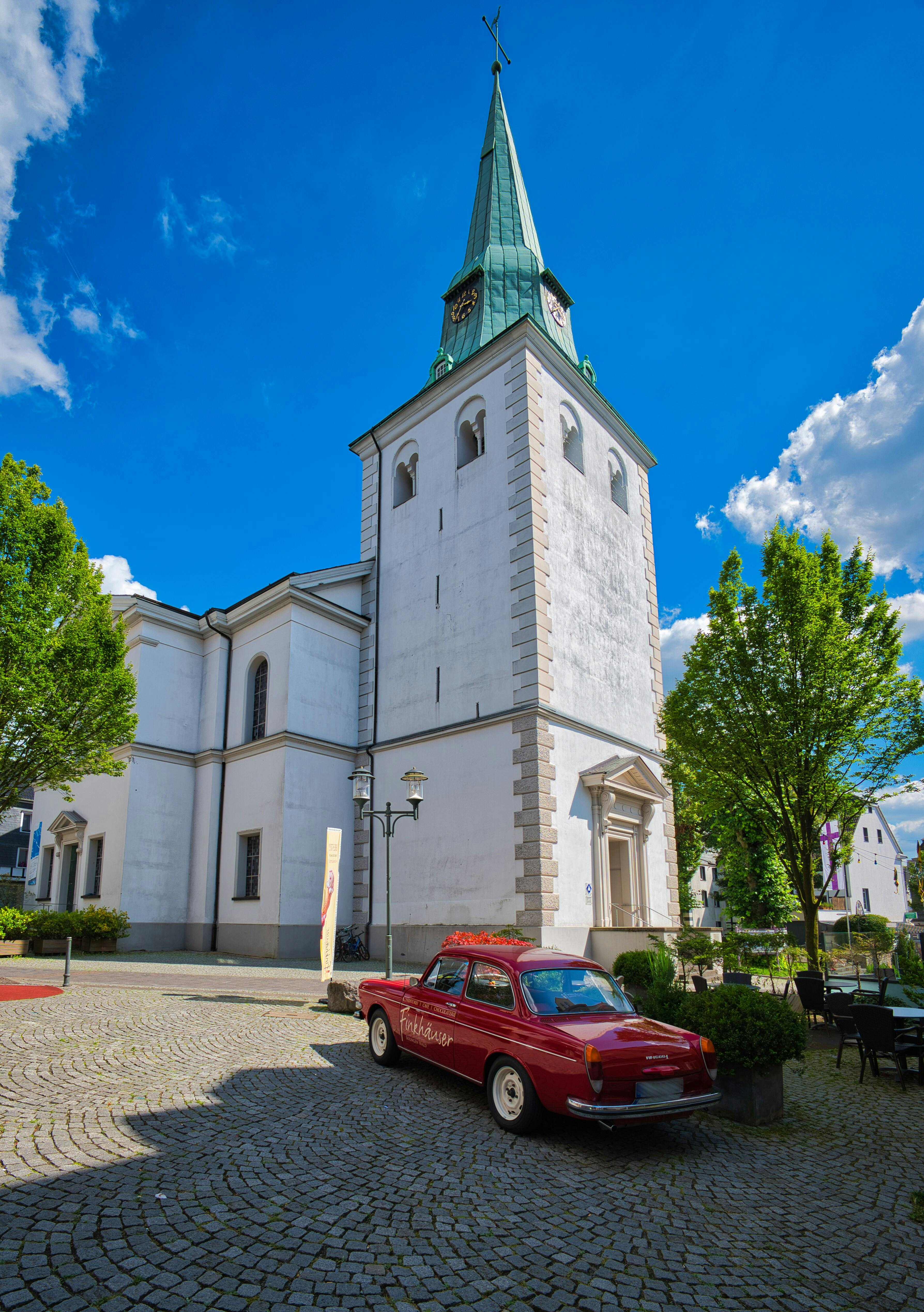A red car parked in front of a church · Free Stock Photo