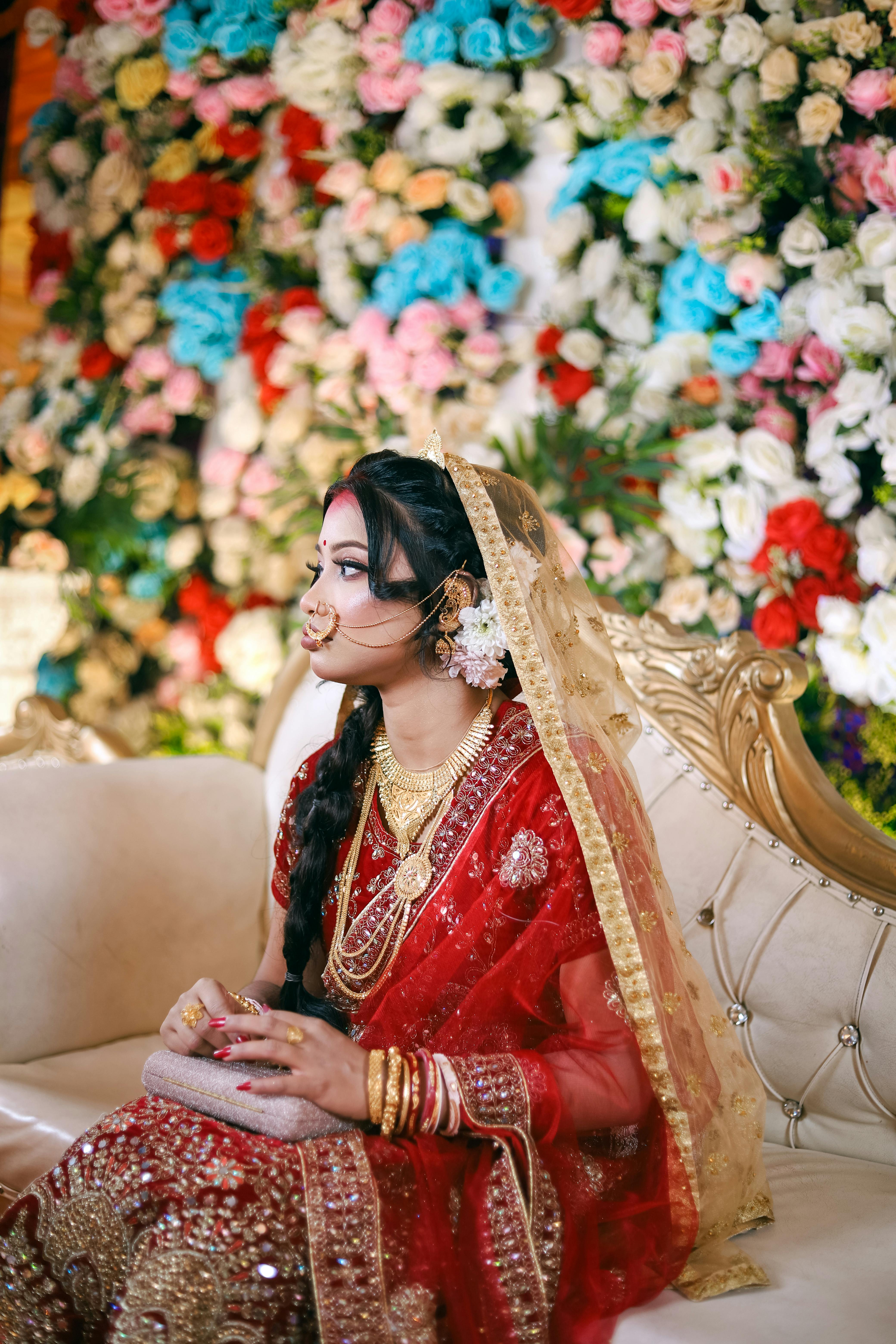 A bride in traditional red and gold attire sitting on a couch · Free ...