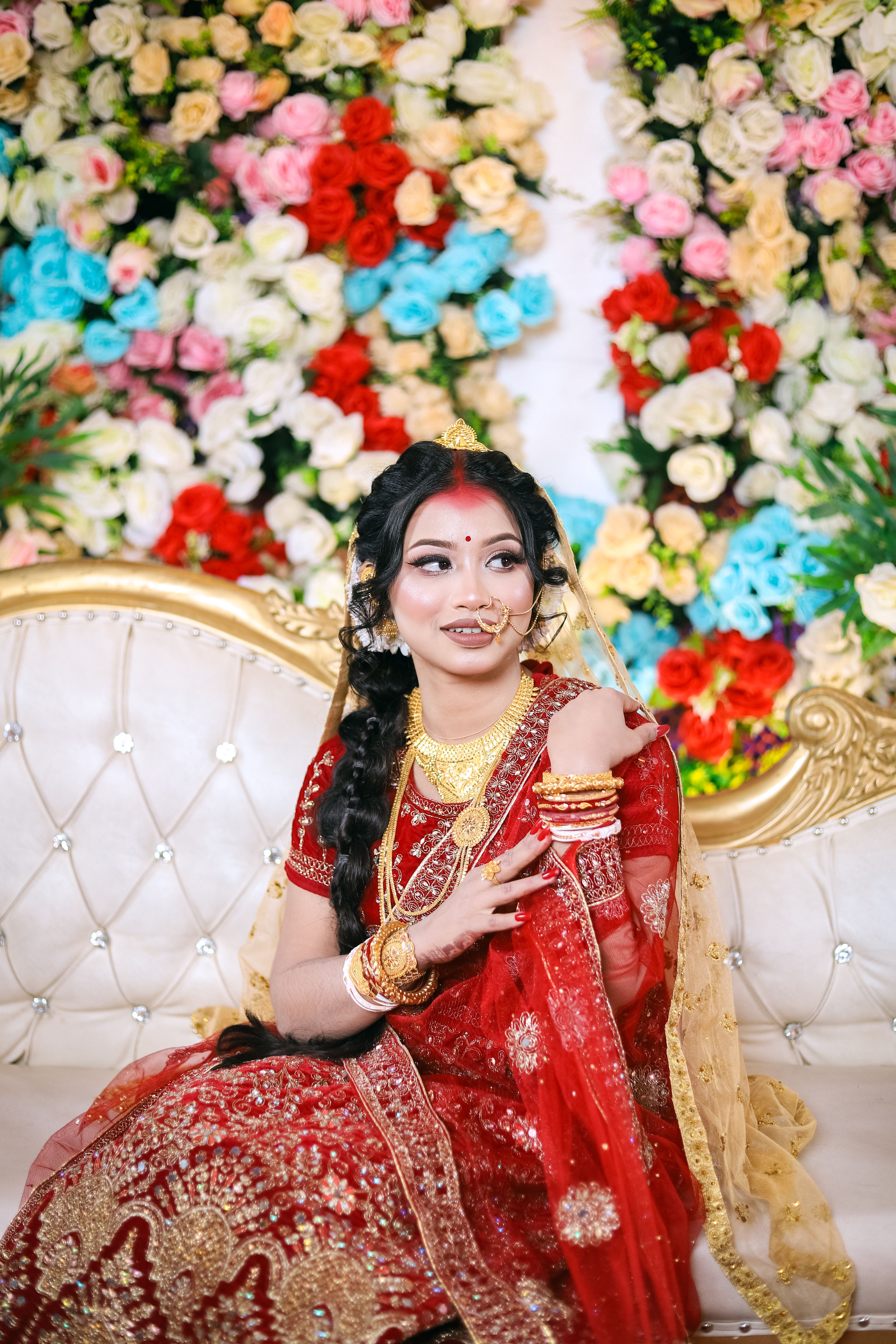 A bride in red and gold sari sitting on a couch · Free Stock Photo