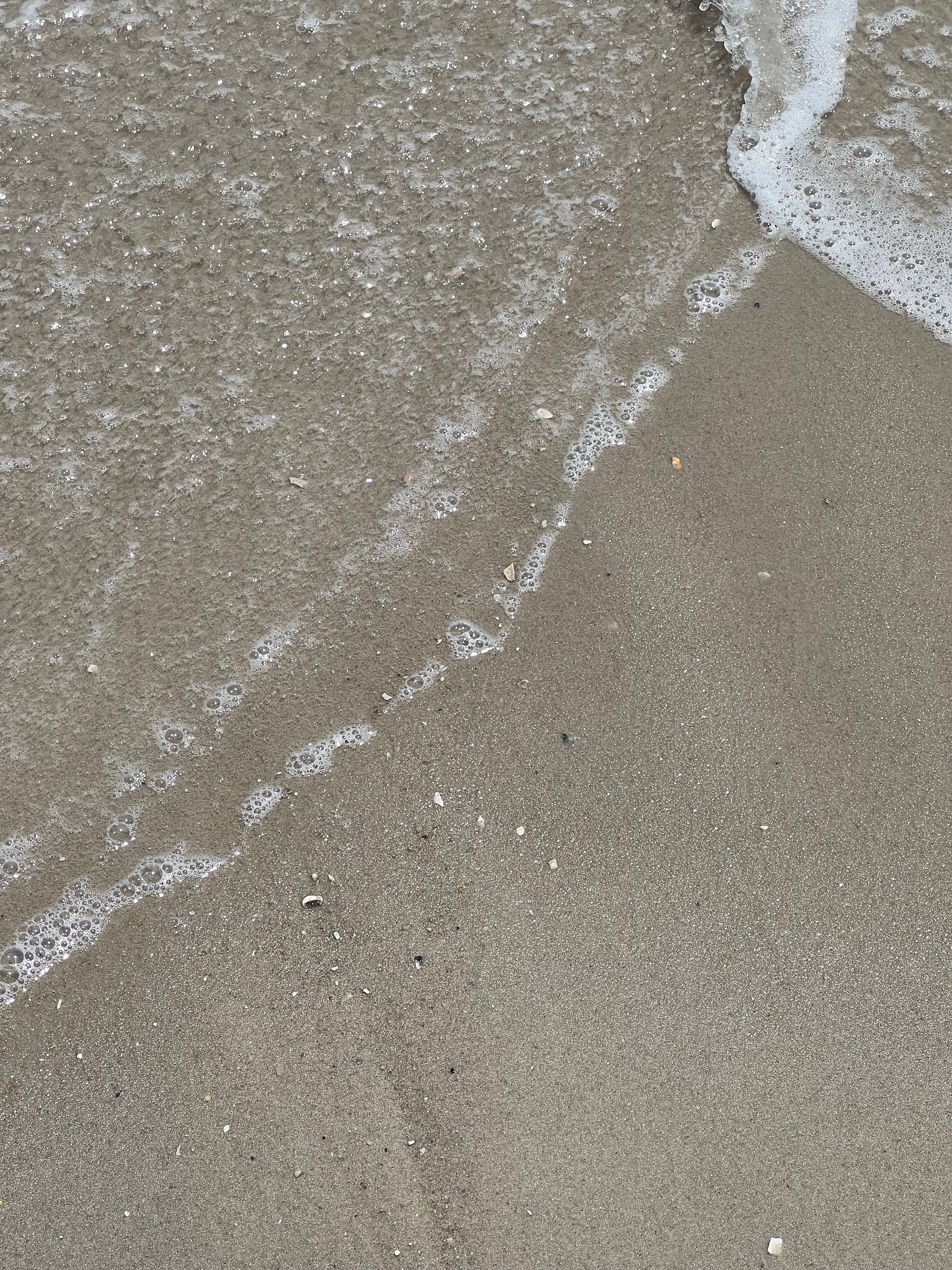 A close up of the sand and water on the beach · Free Stock Photo
