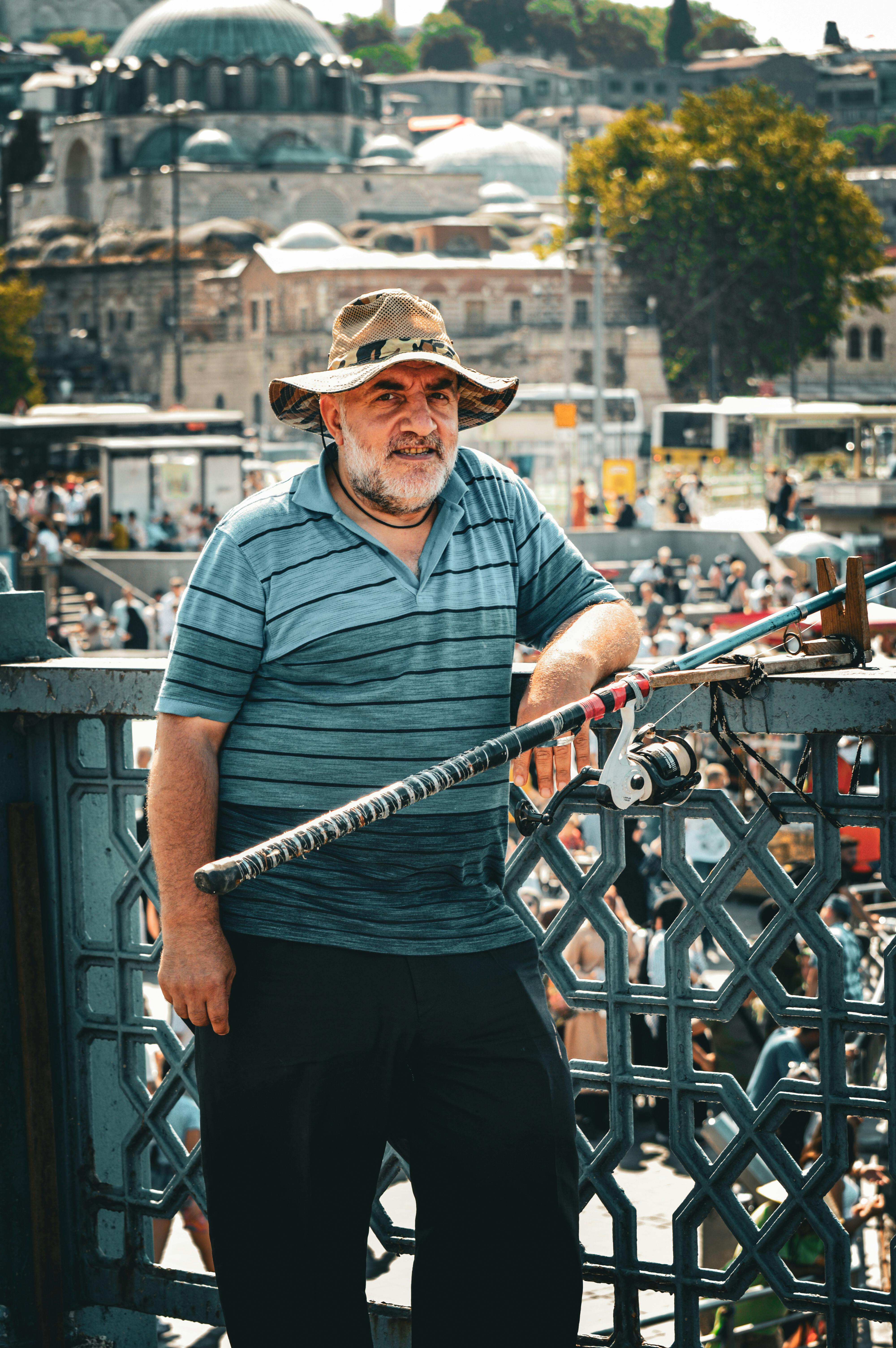 A man with a hat and a long beard standing on a bridge · Free Stock Photo