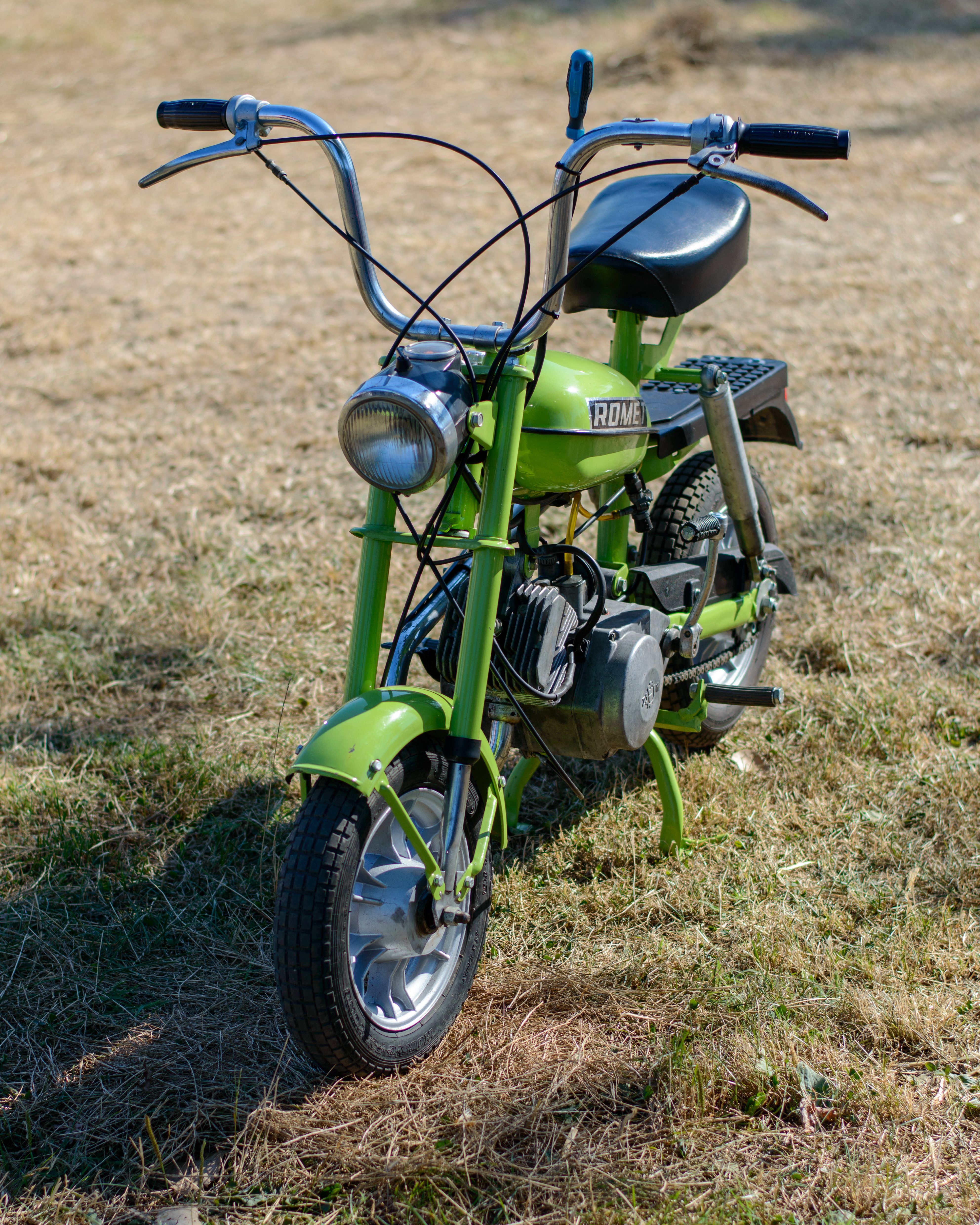 A green motorcycle parked in a grassy field · Free Stock Photo