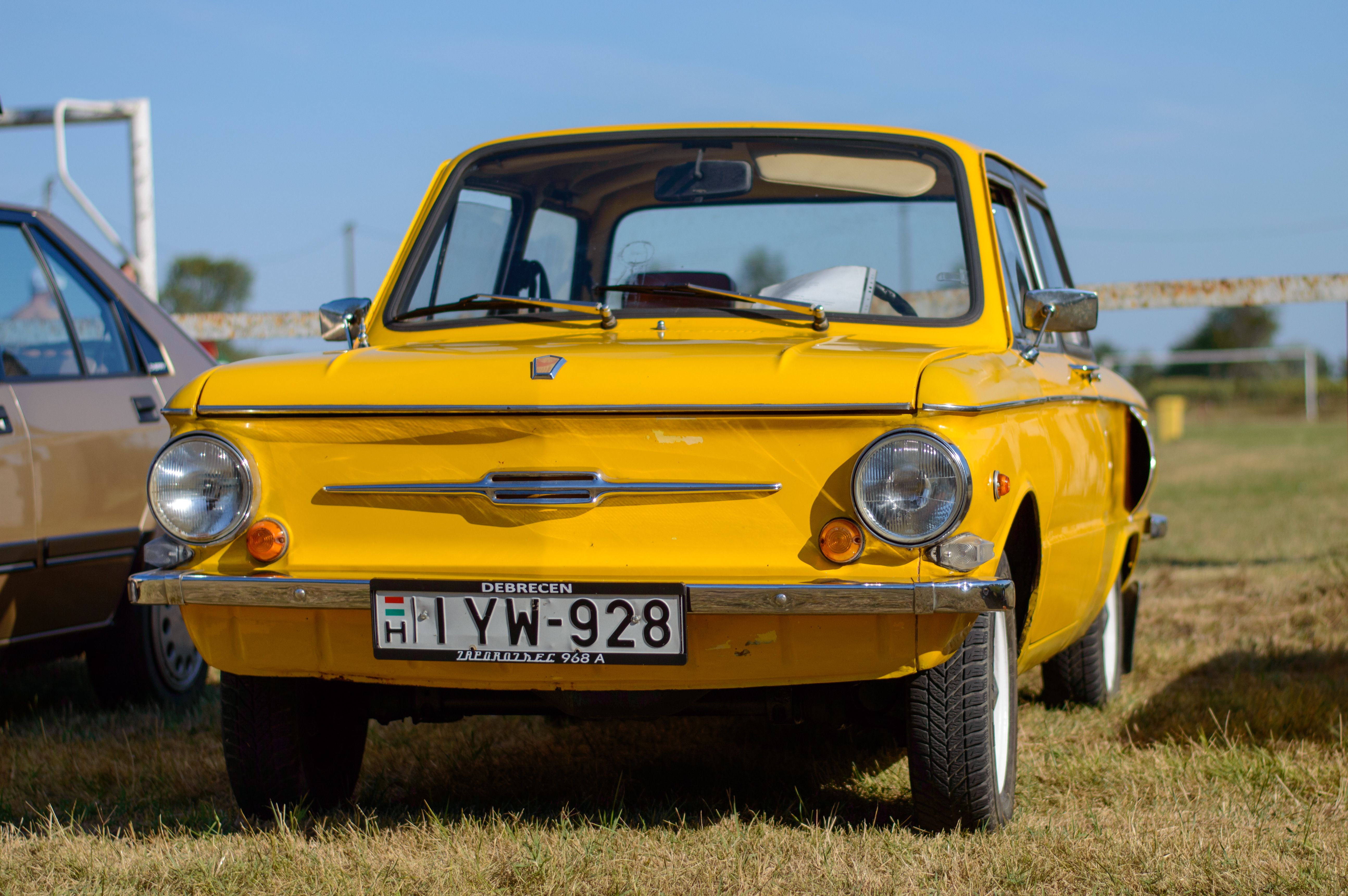 A yellow car parked in the grass next to a few other cars · Free Stock ...