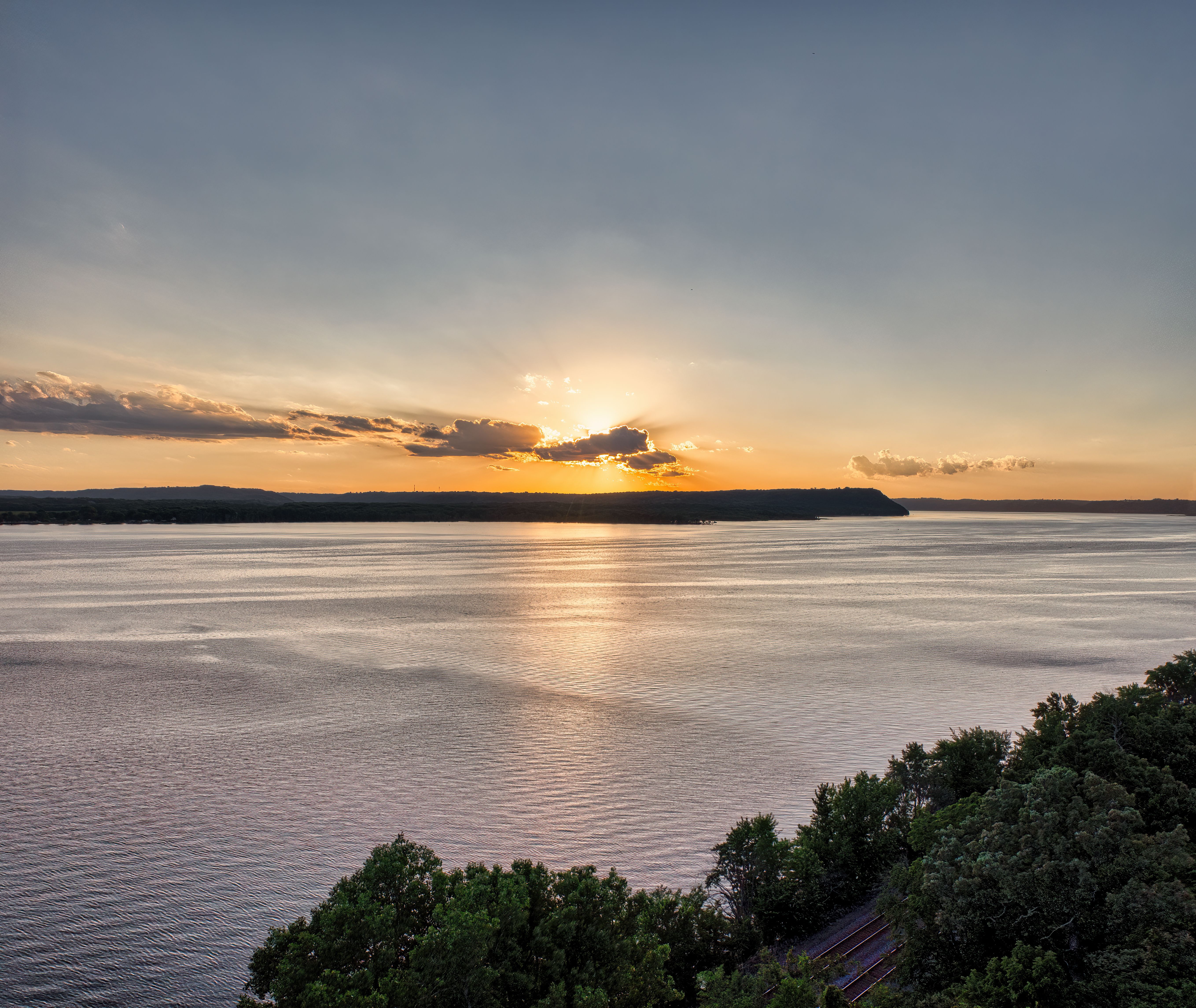 A sunset over a body of water with trees · Free Stock Photo