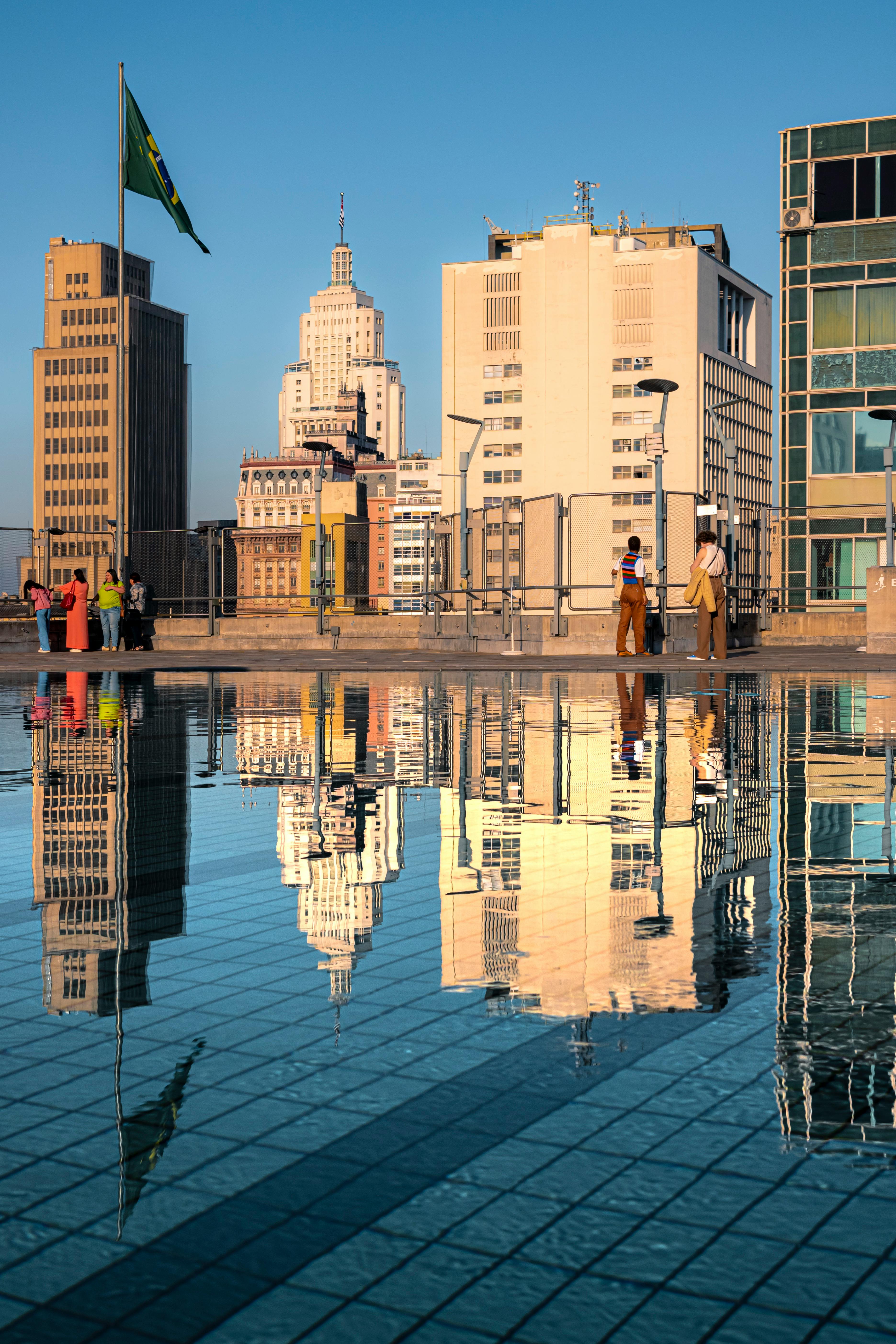 A reflection of buildings in a pool with people · Free Stock Photo