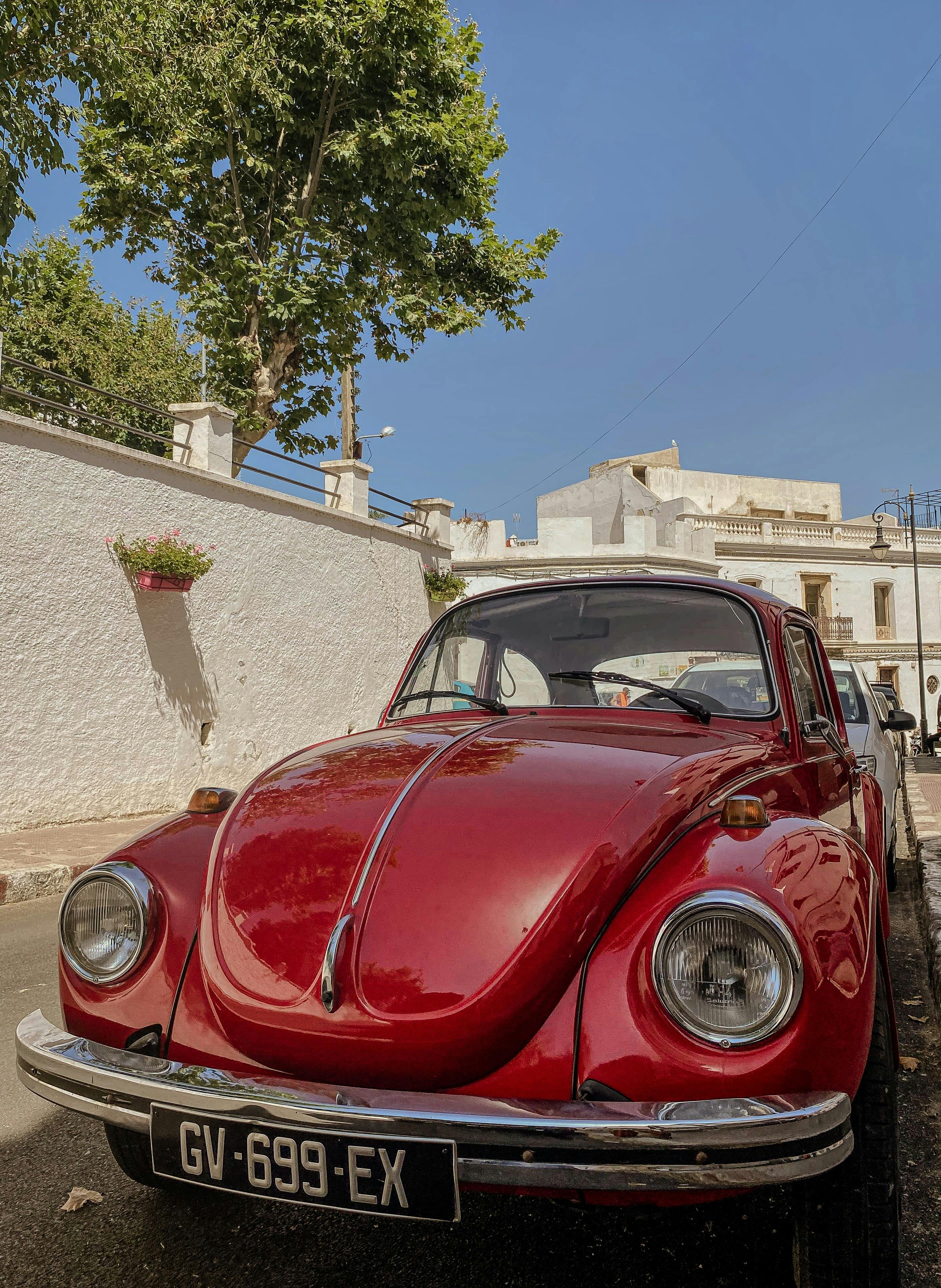 A red volkswagen beetle parked on a street · Free Stock Photo
