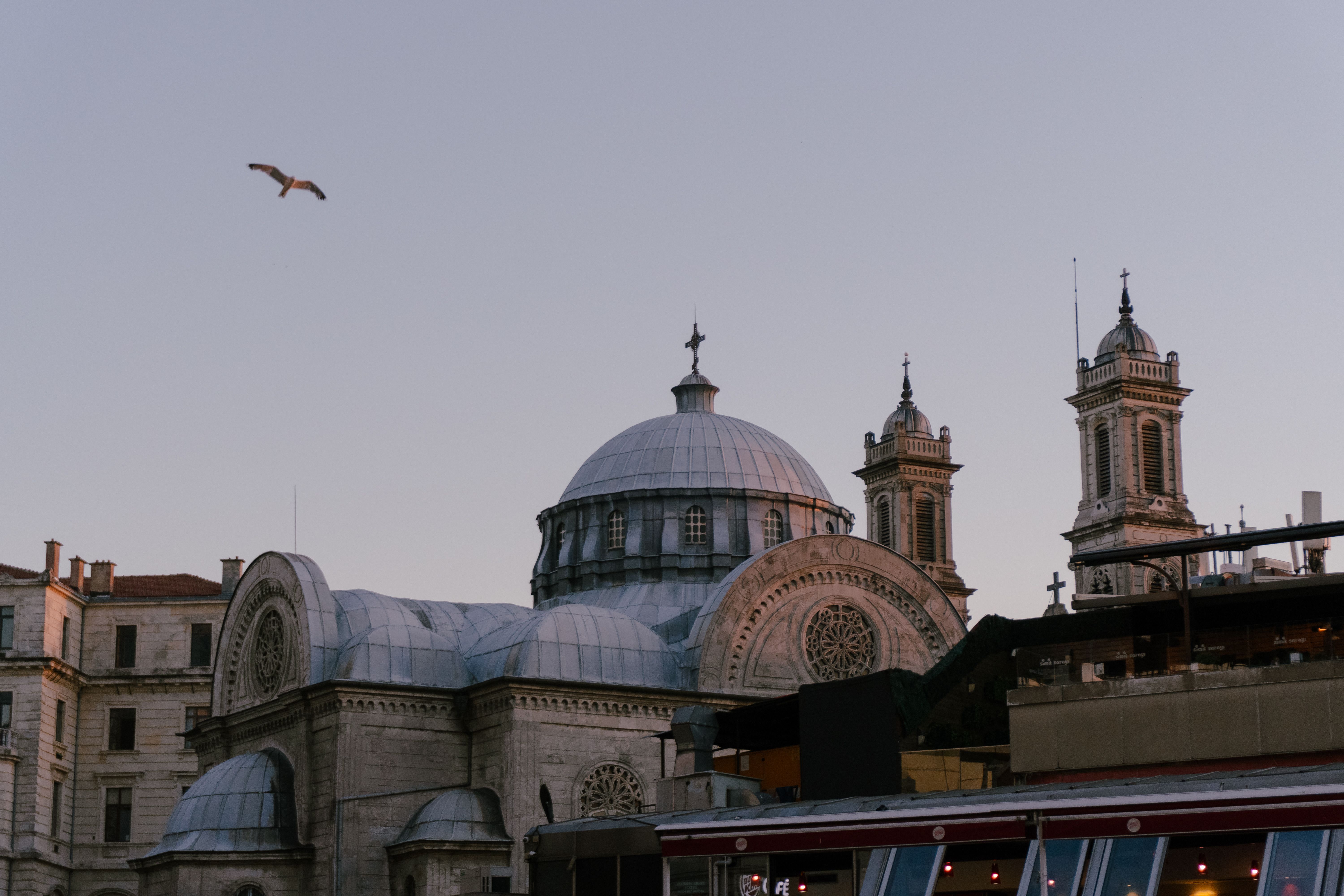 A bird flying over a church in the city · Free Stock Photo