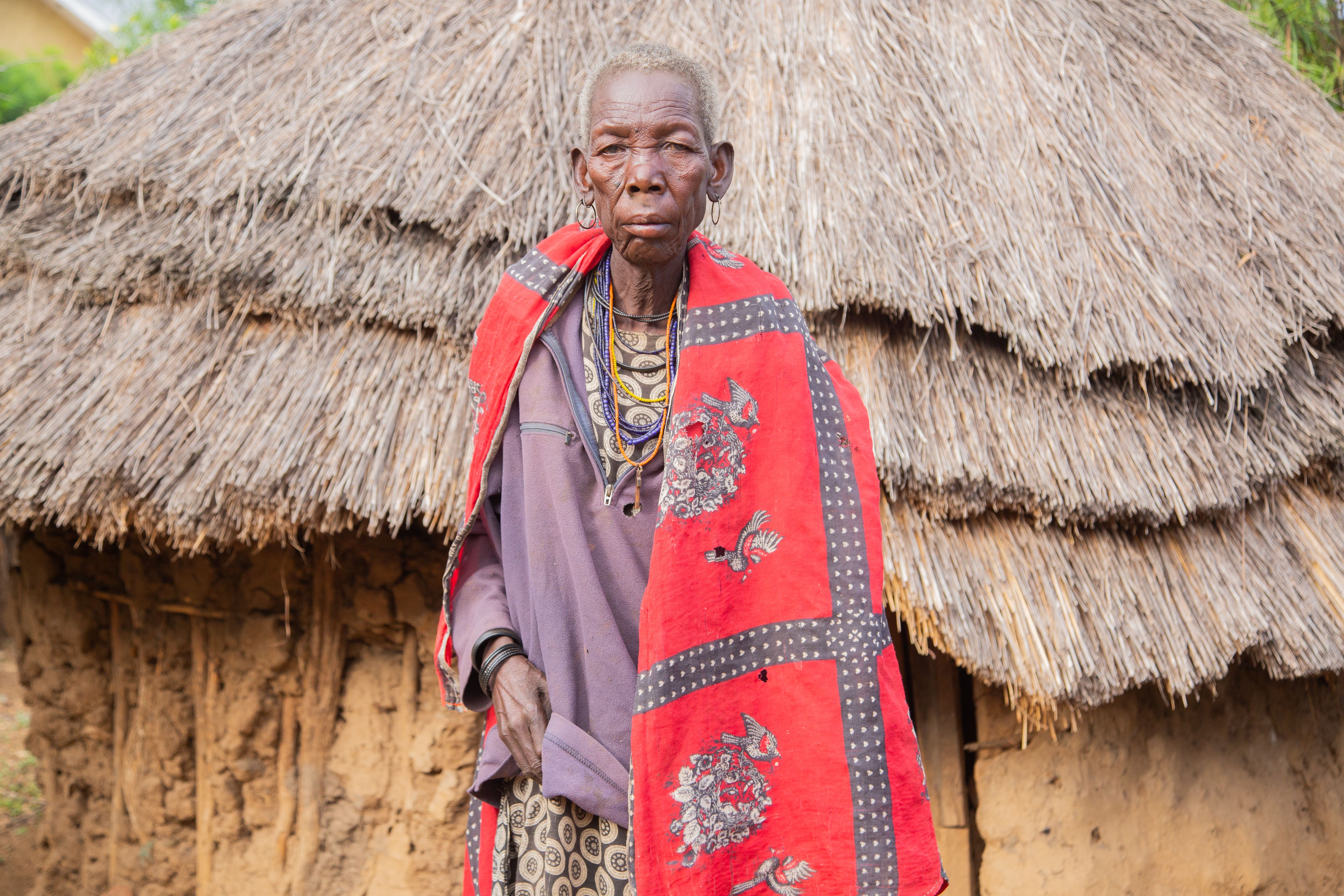 An old woman standing in front of a hut · Free Stock Photo