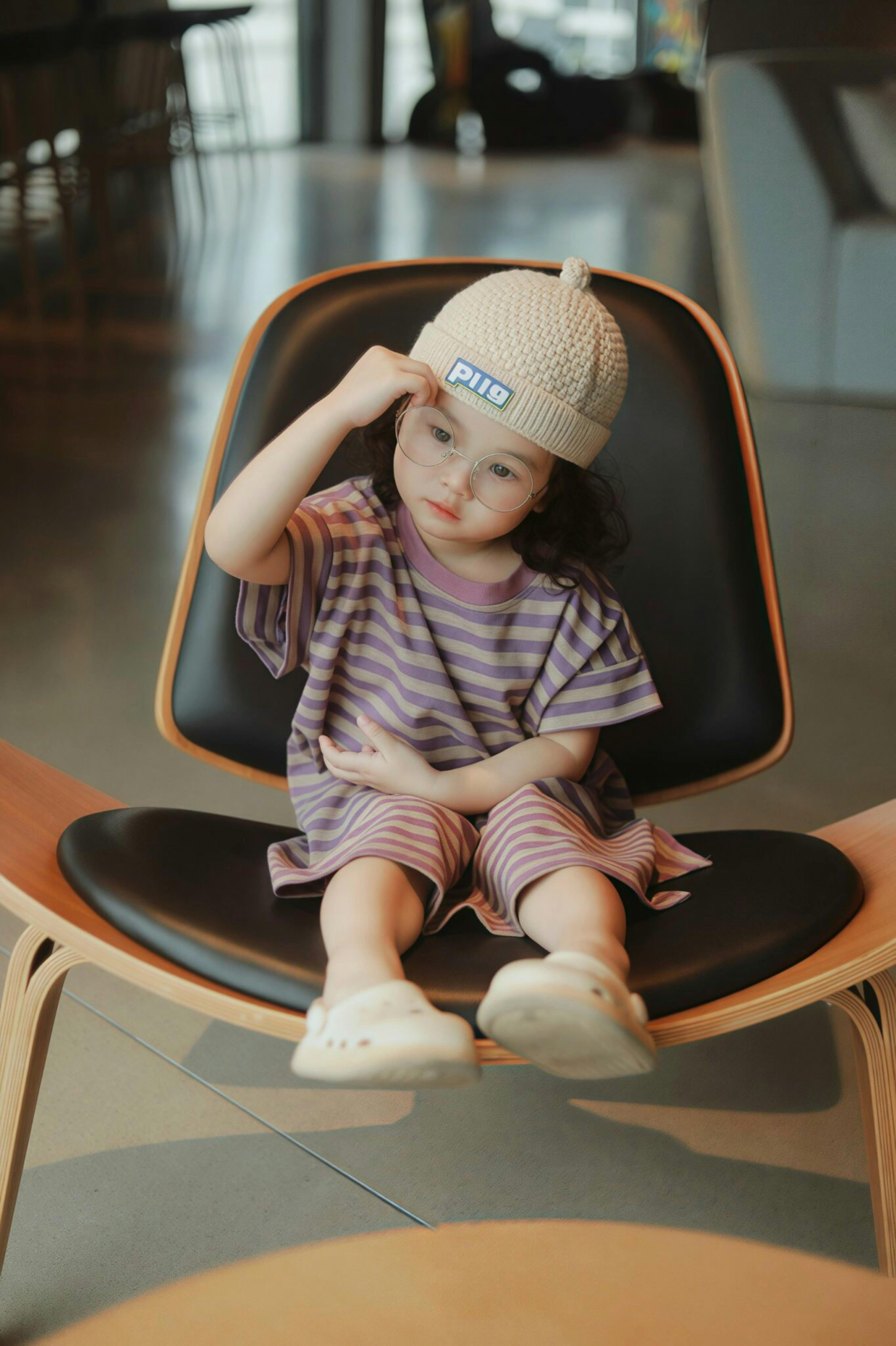 A little girl sitting on a chair wearing a hat · Free Stock Photo