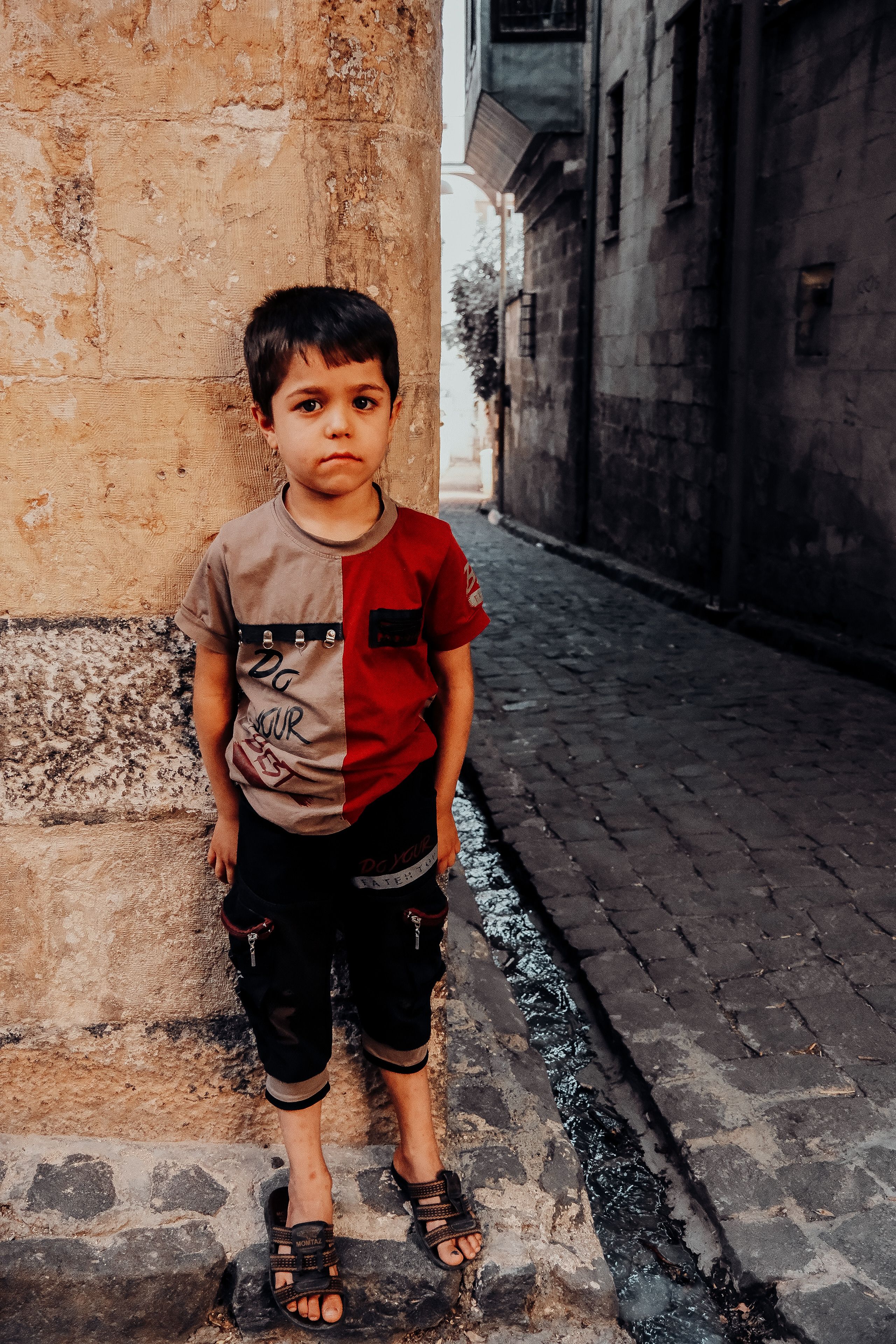 A young boy standing in the middle of a narrow alley · Free Stock Photo