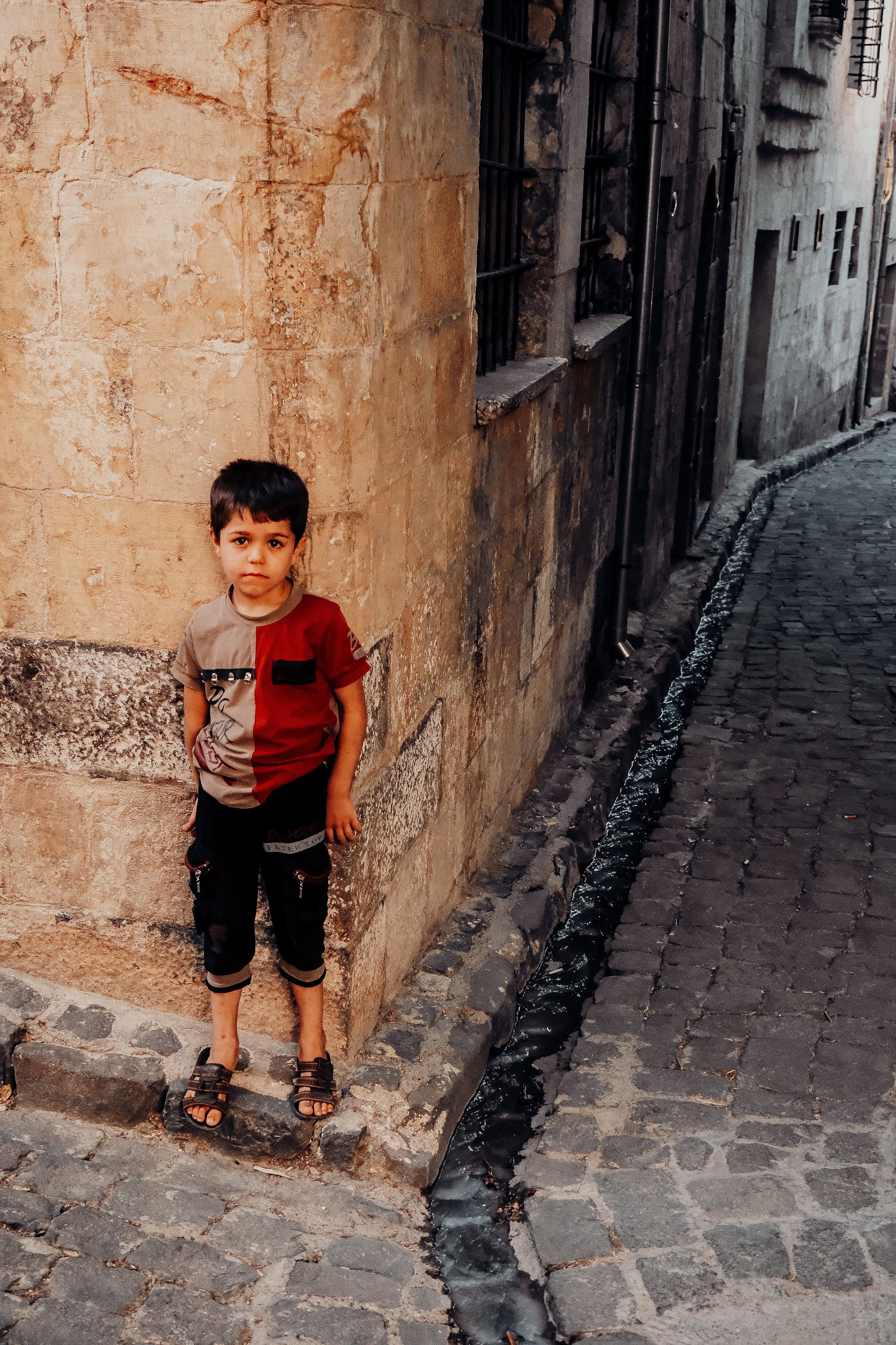 A young boy standing on a narrow alley · Free Stock Photo