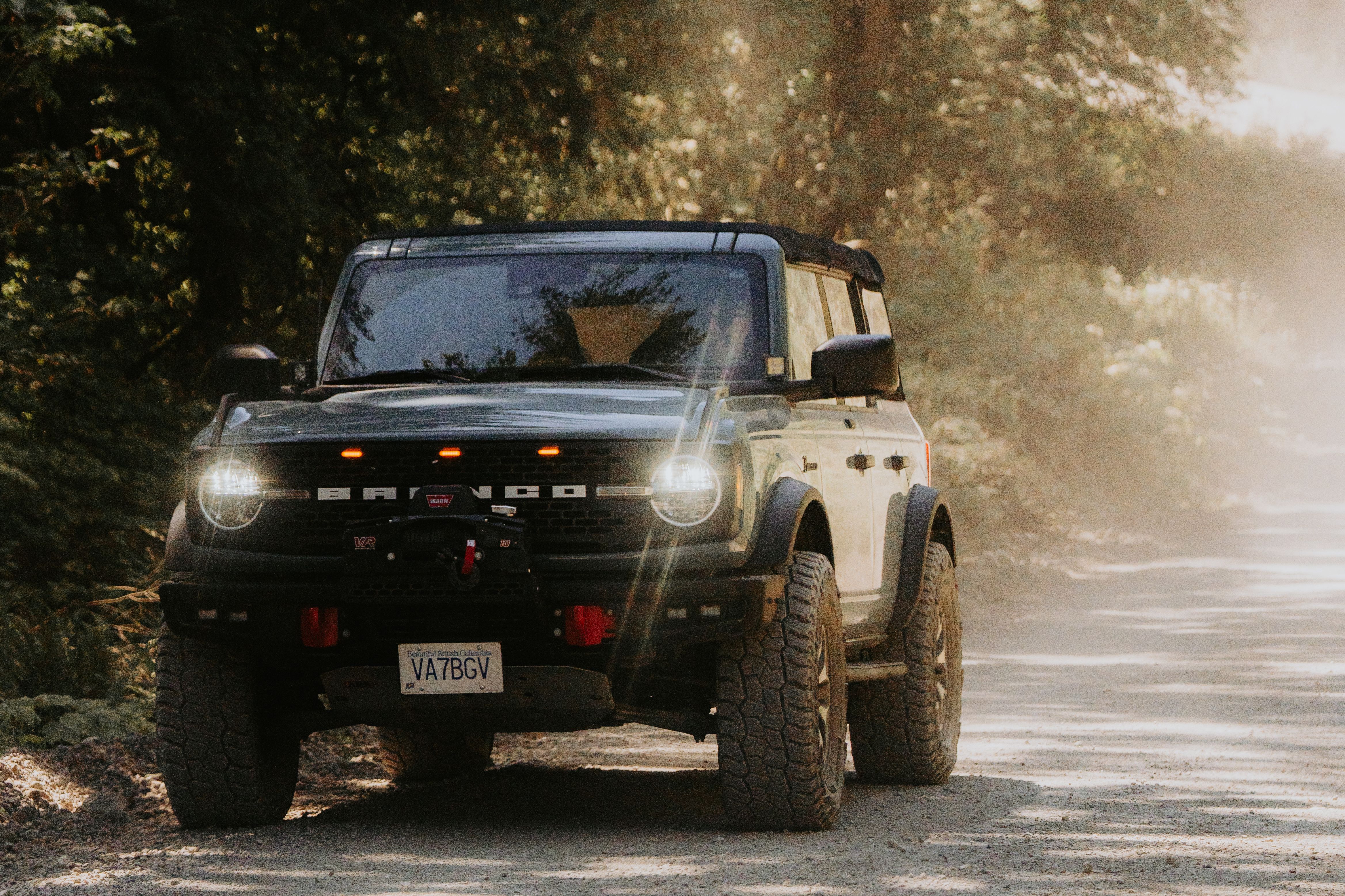 A black suv driving down a dirt road · Free Stock Photo
