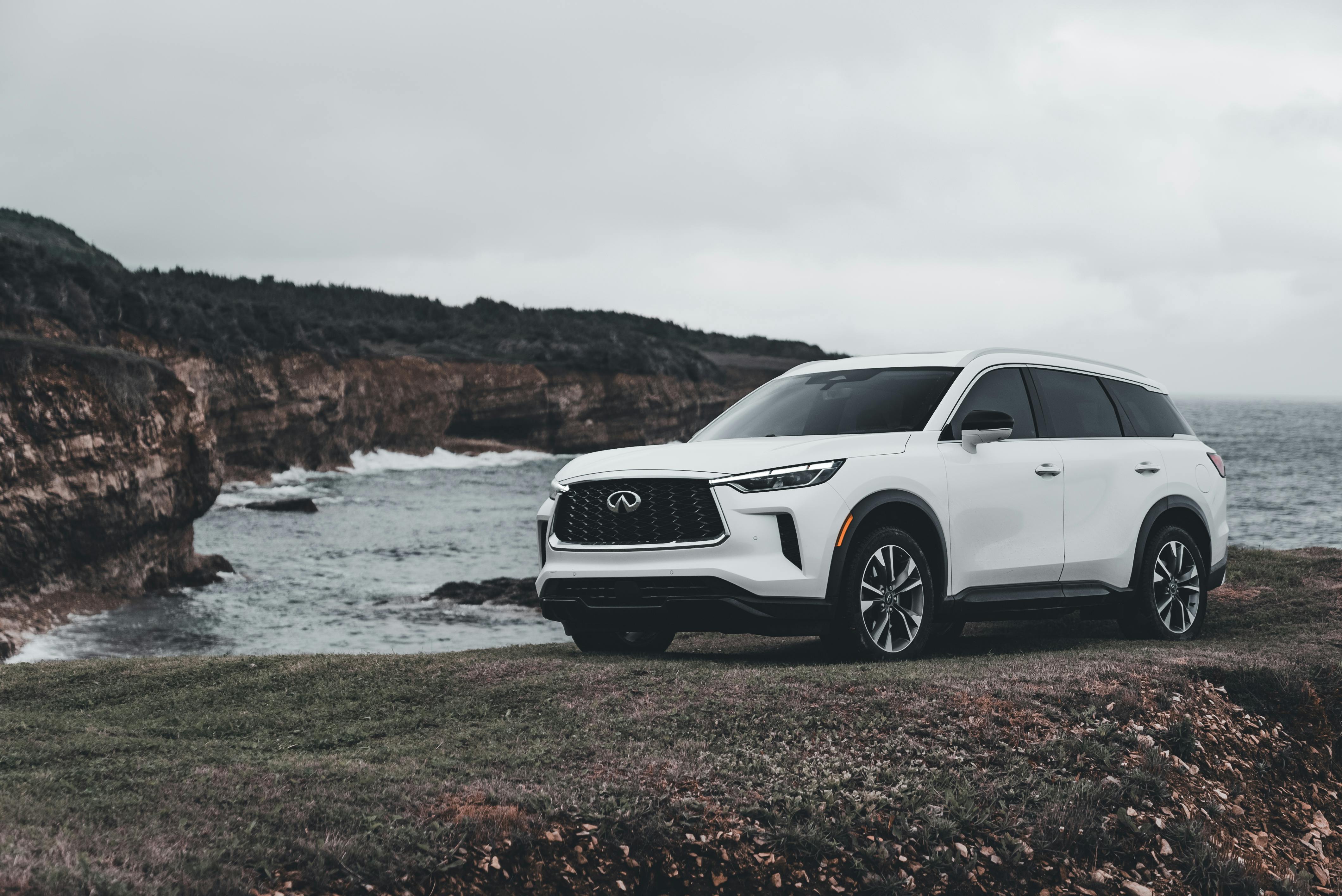 The 2020 infiniti suv parked on a rocky beach · Free Stock Photo