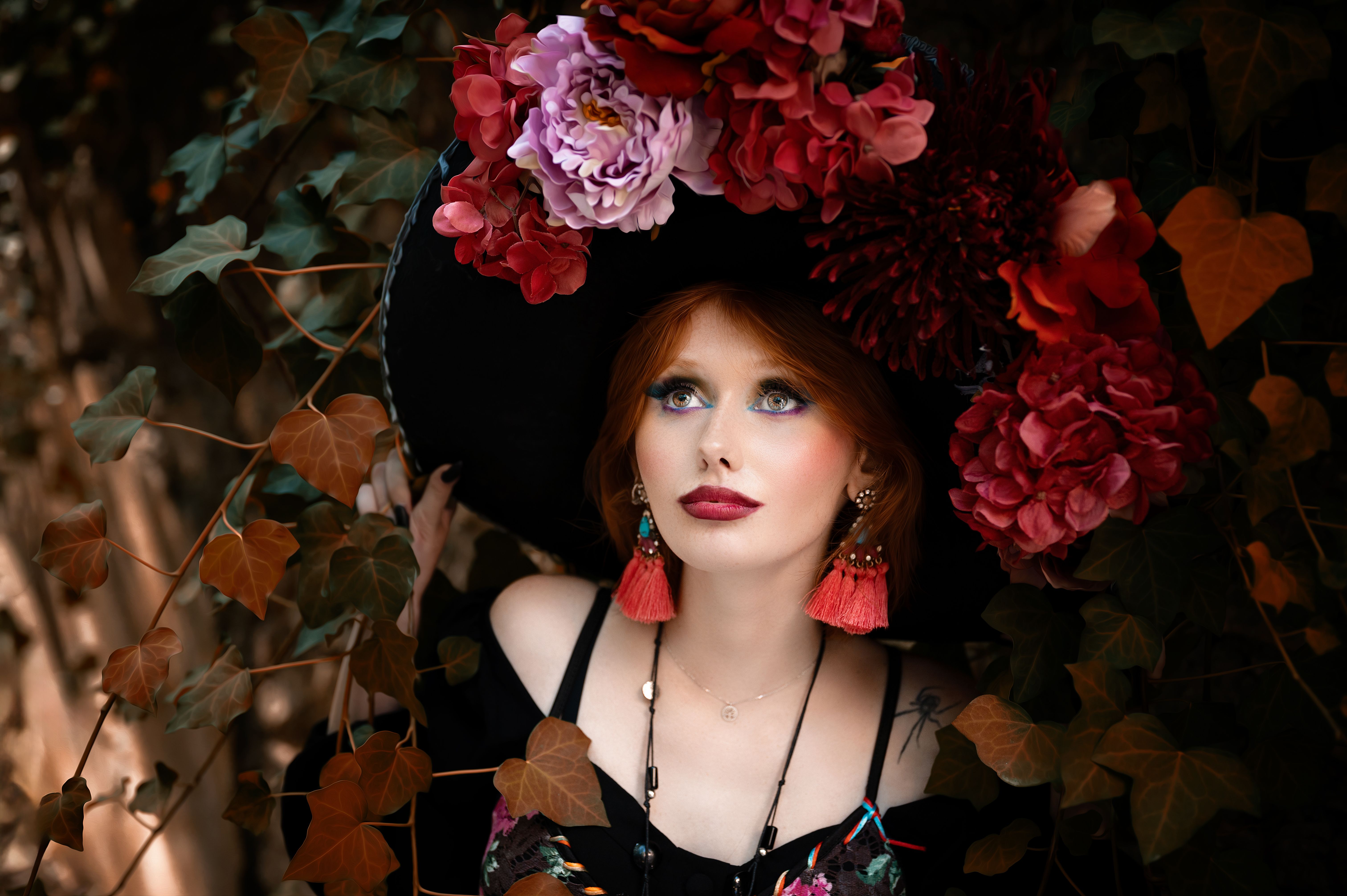 A woman wearing a large hat and red flowers · Free Stock Photo