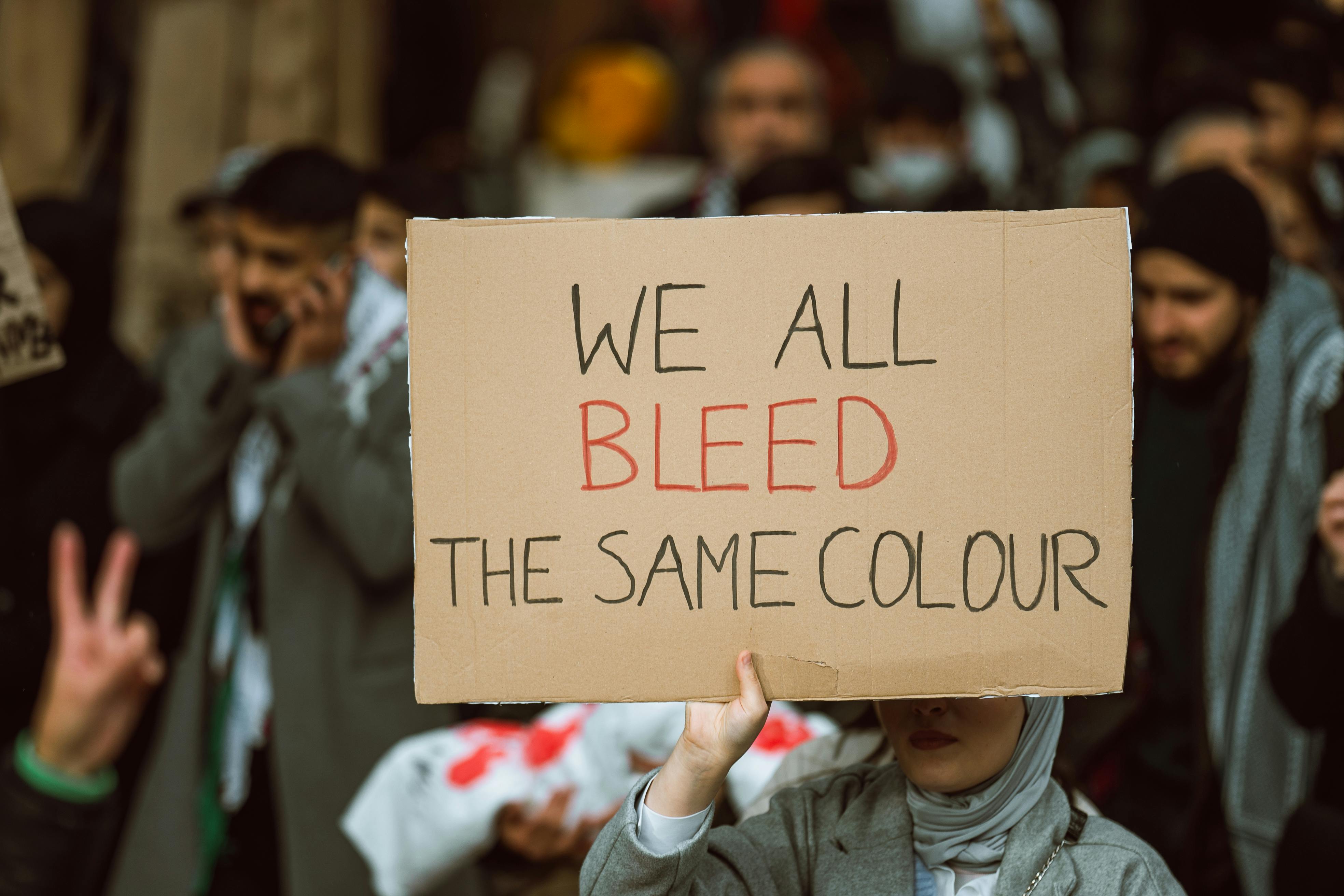 A person holding a sign that says we all bleed the same colour · Free ...
