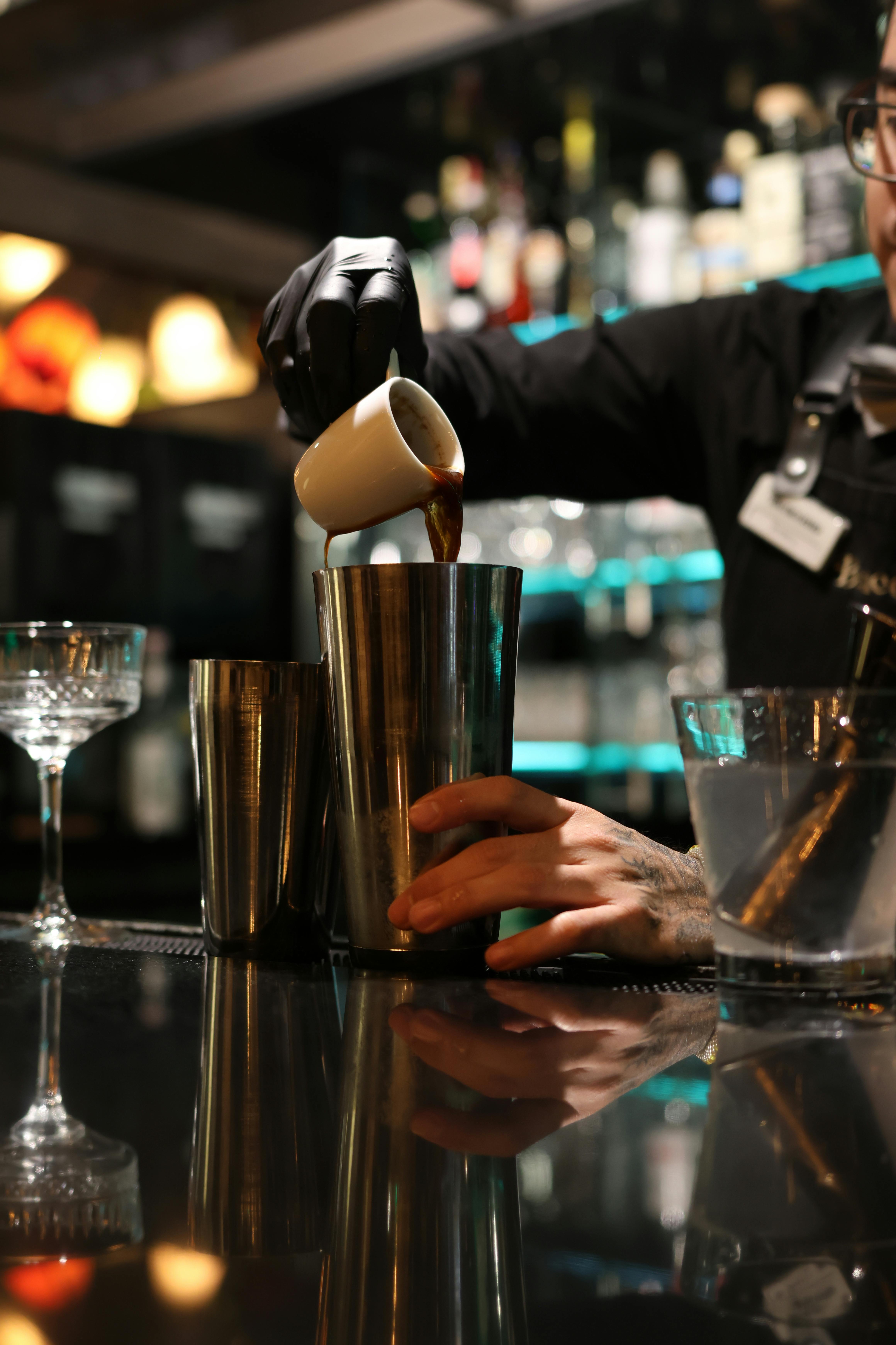 A bartender pouring a drink into a glass · Free Stock Photo