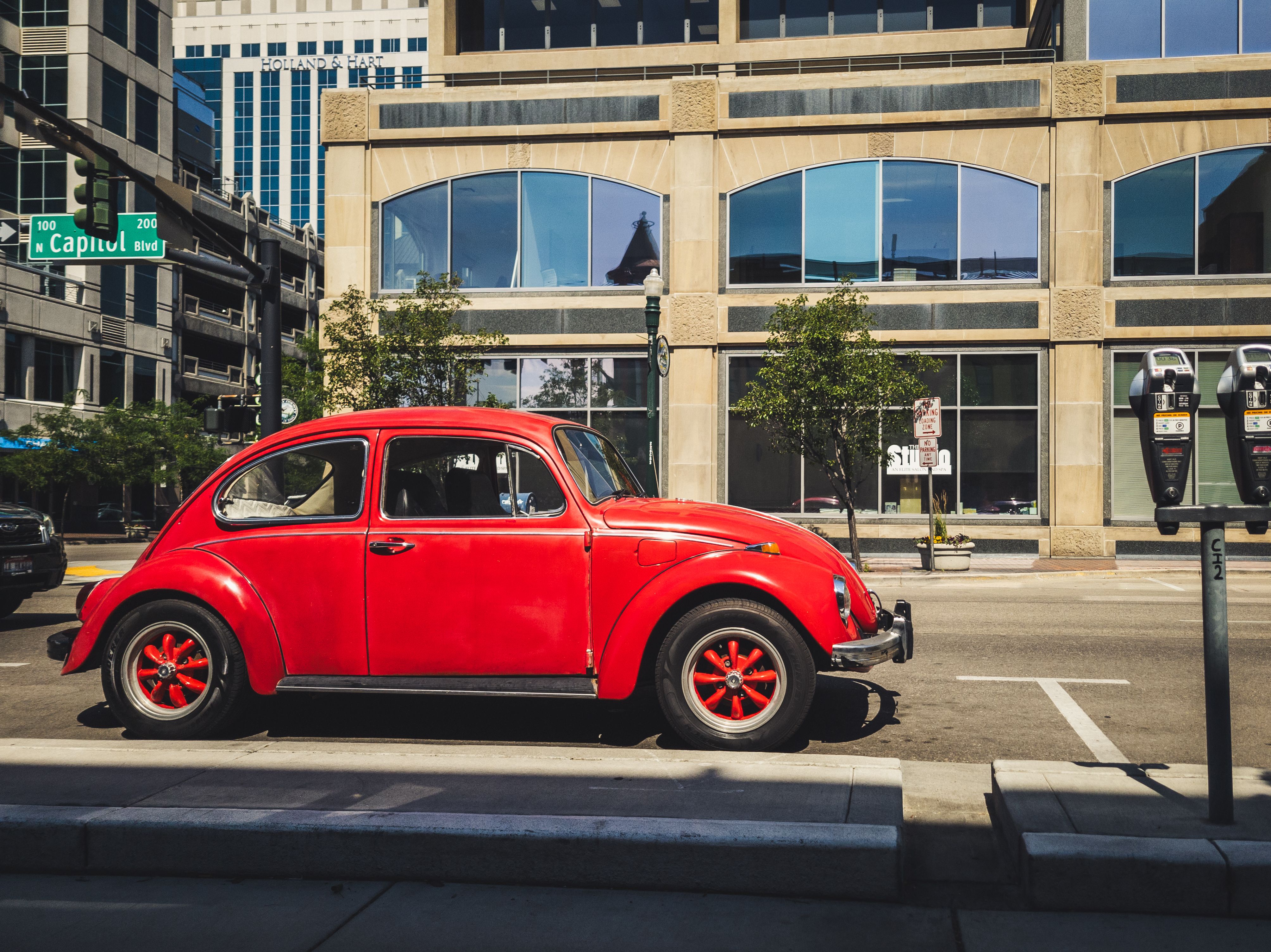 A red volkswagen beetle parked in front of a building · Free Stock Photo