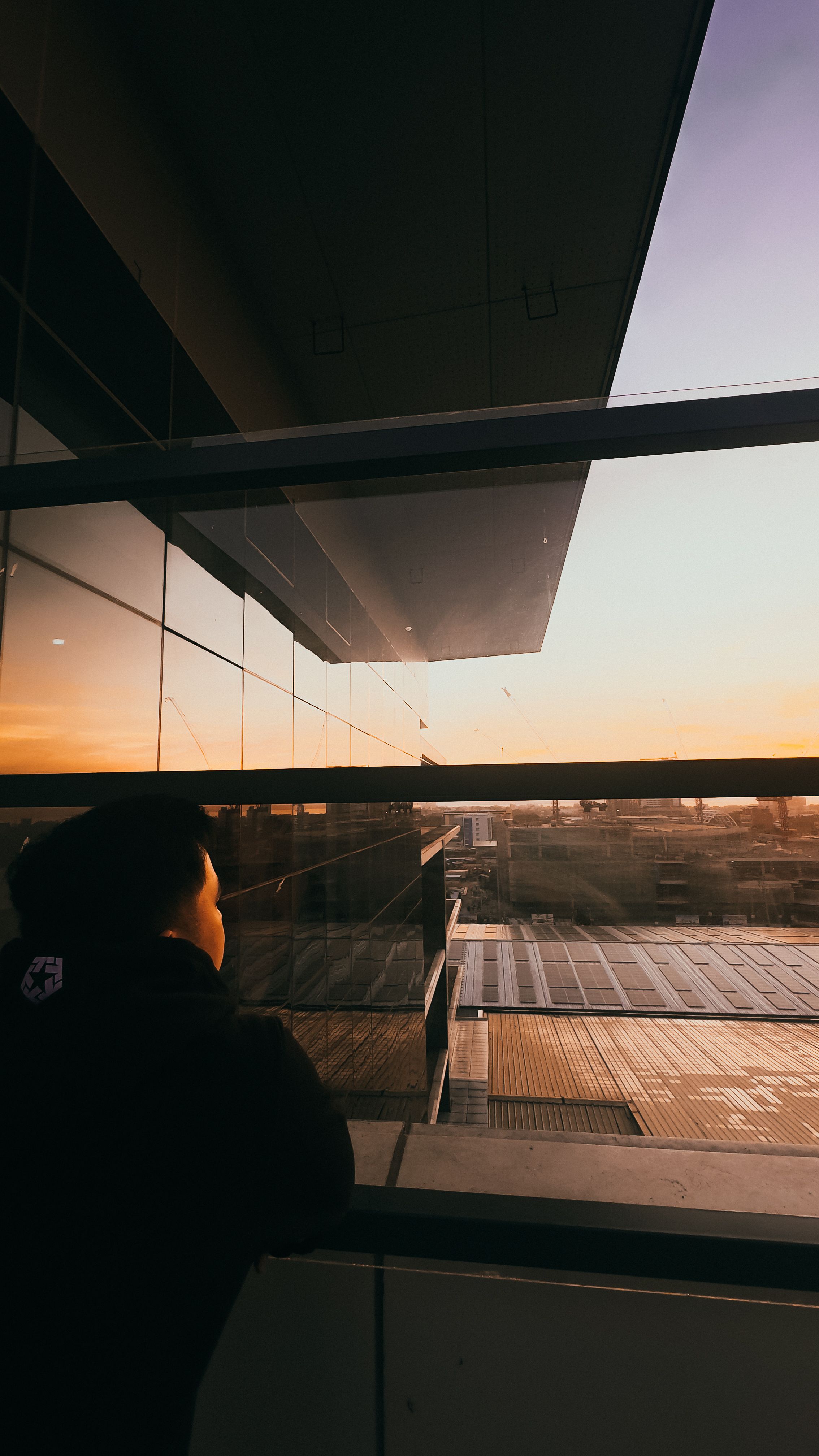 A person looking out of a window at the sunset · Free Stock Photo