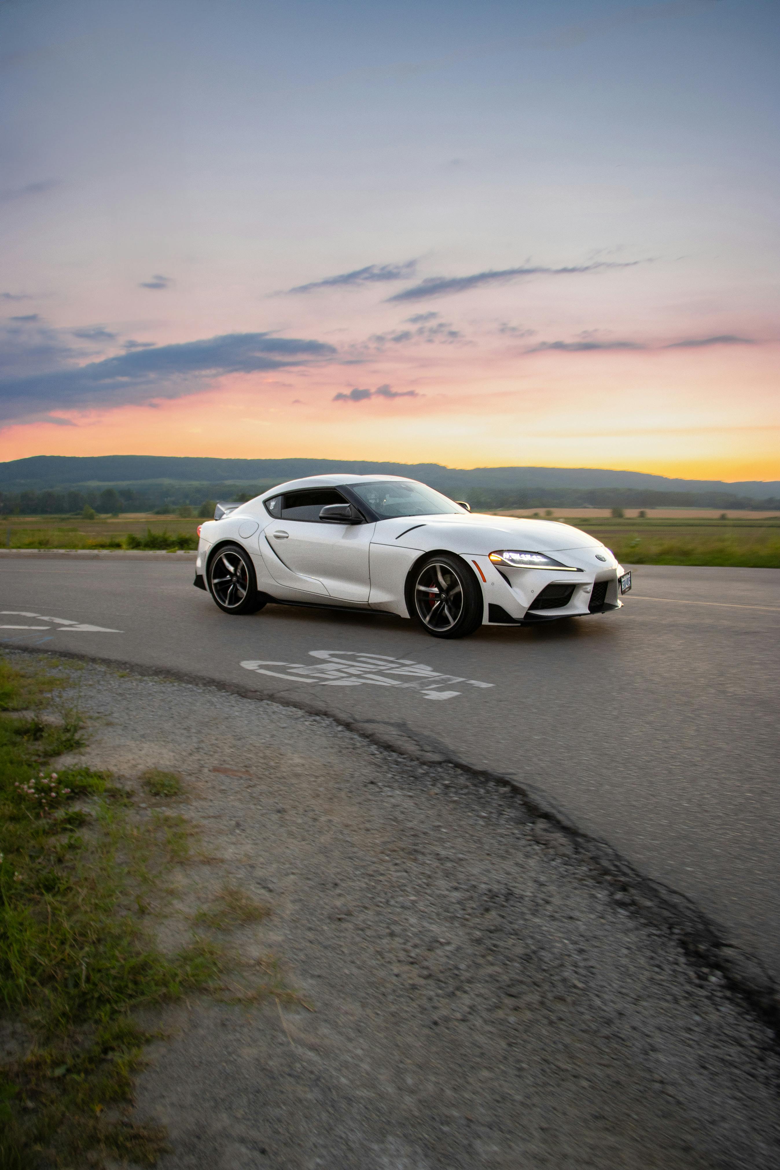 The toyota supra is driving down a road at sunset · Free Stock Photo