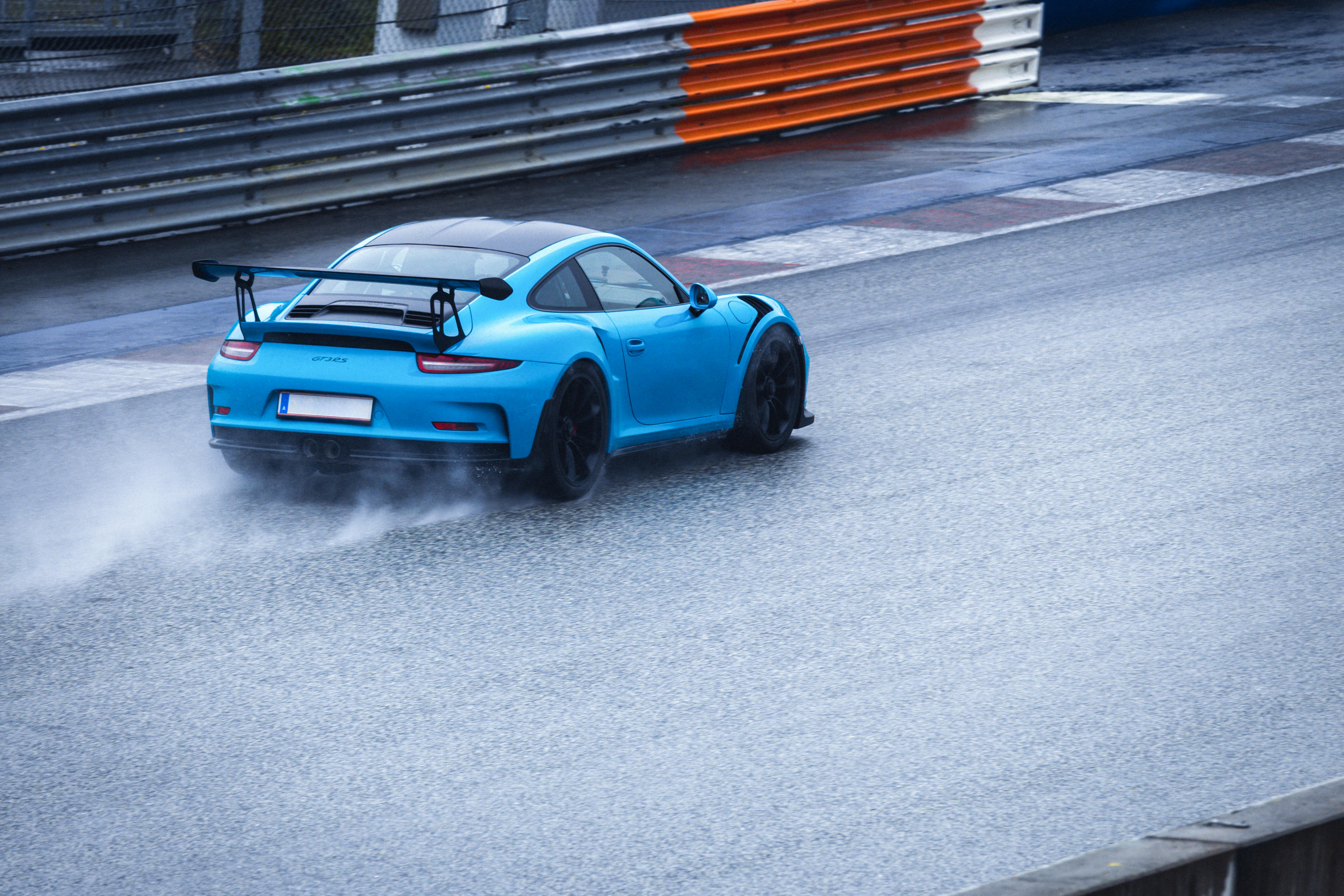 A blue porsche 911 gt3 is driving on the track · Free Stock Photo