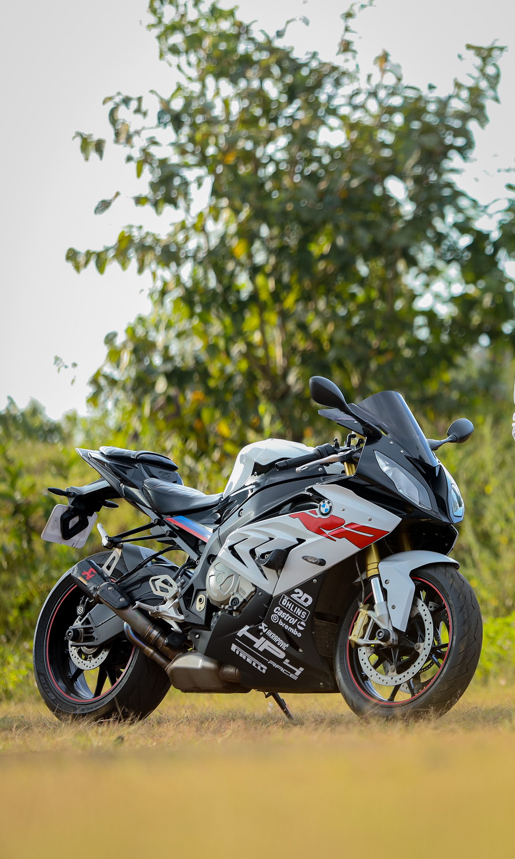 A motorcycle parked in a field with trees and grass · Free Stock Photo
