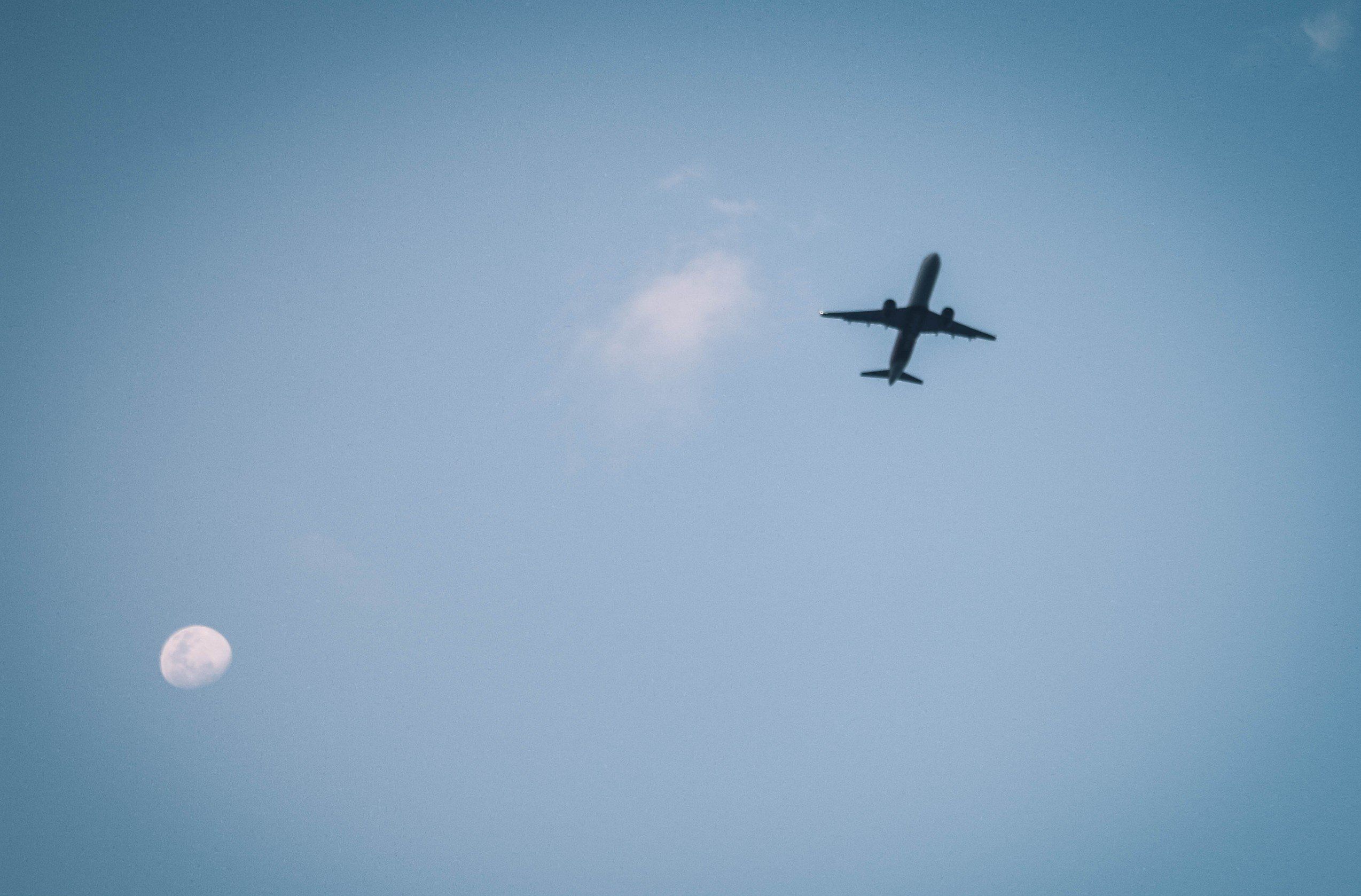 A plane flying in the sky with a moon in the background · Free Stock Photo