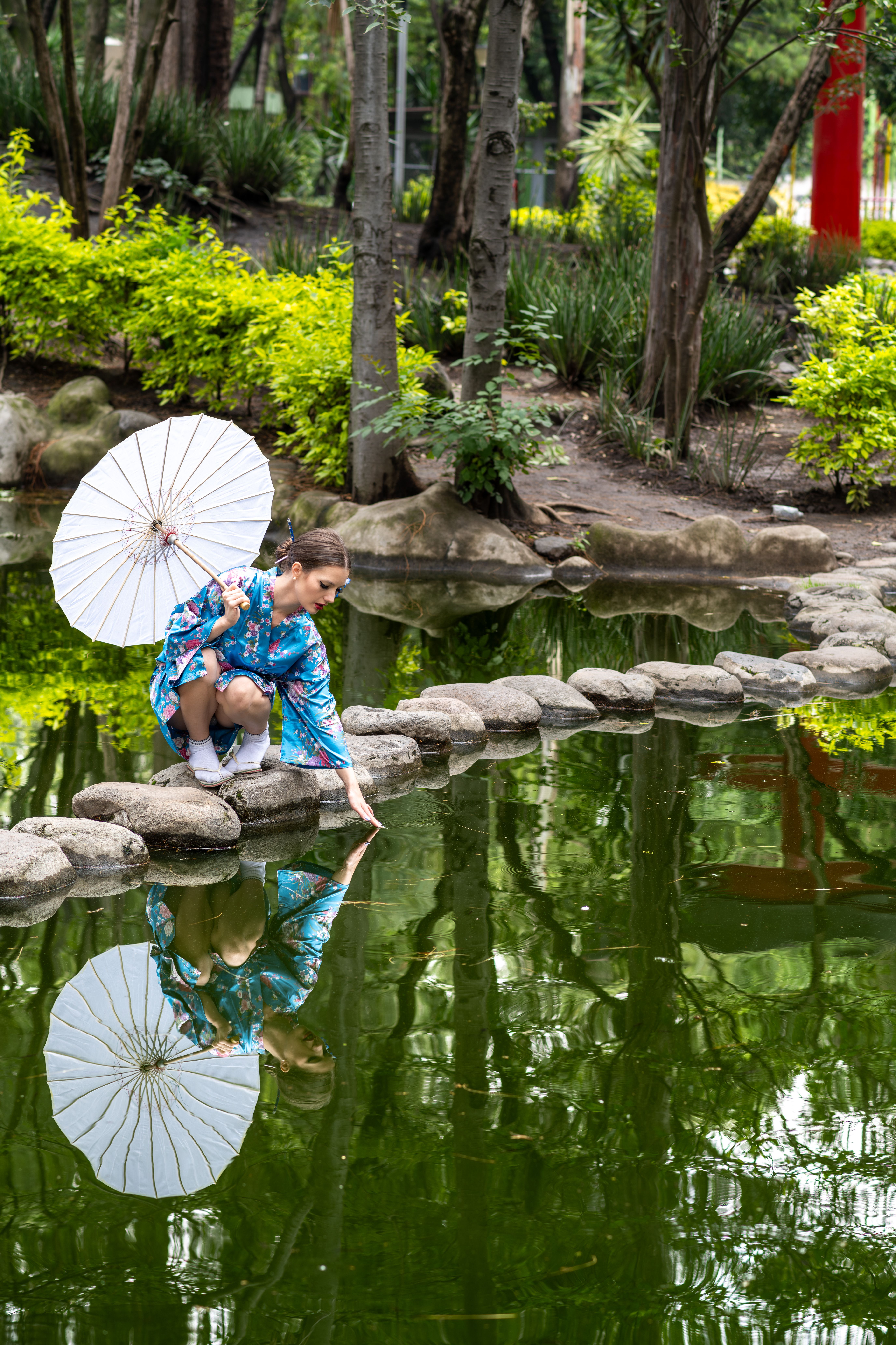 A young girl in traditional japanese clothing is standing on a bridge ...