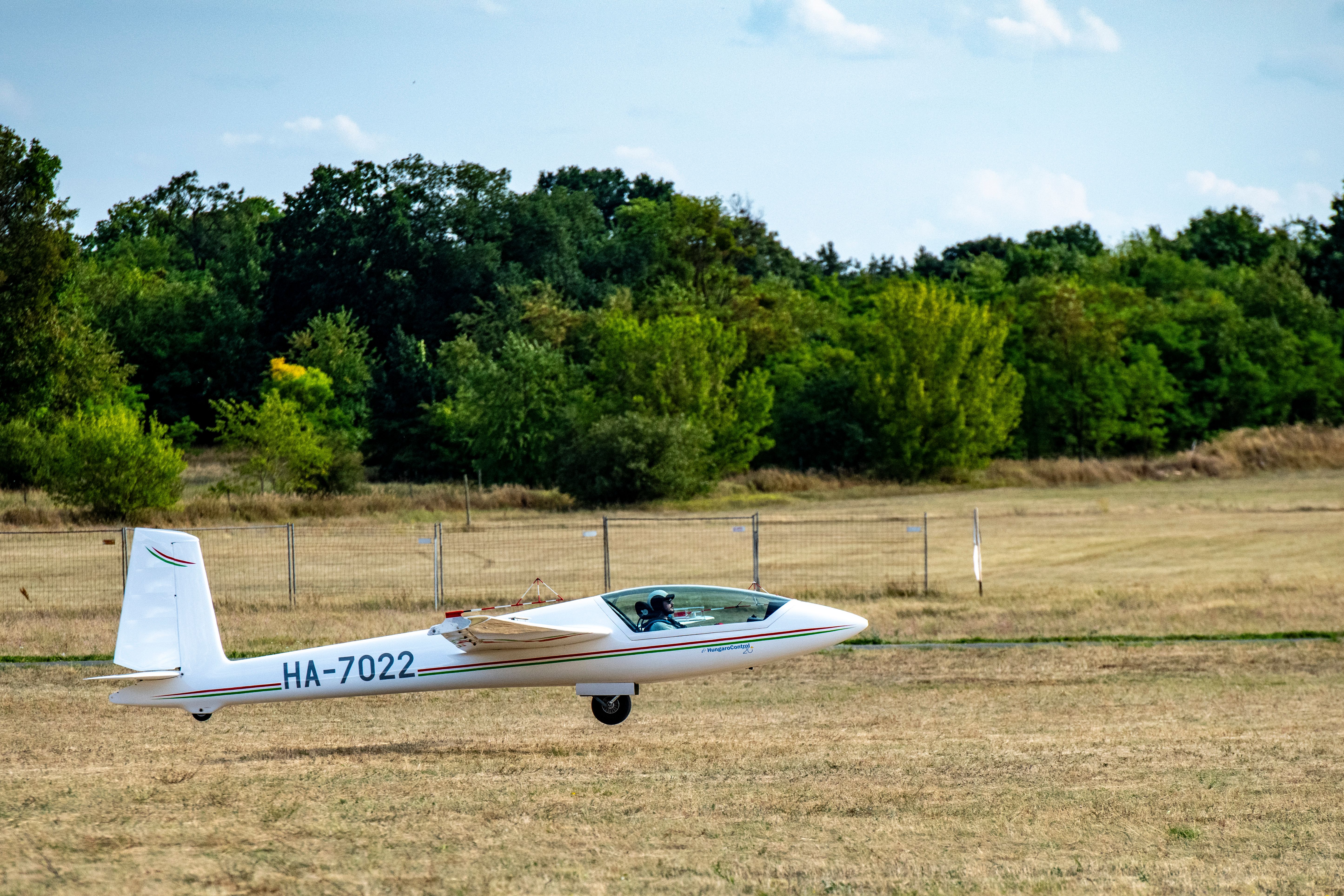 A small plane is flying over a field · Free Stock Photo