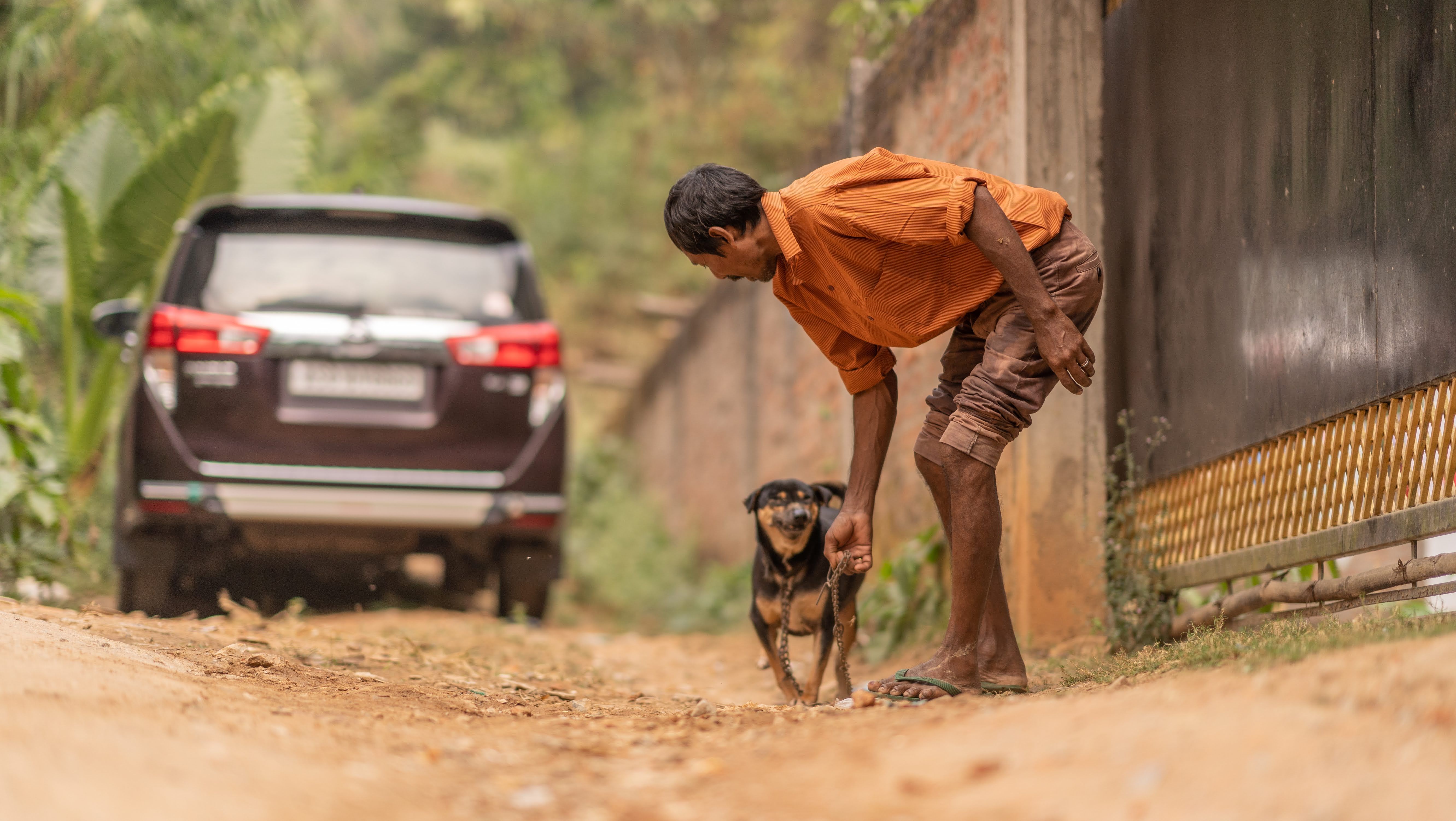 A man walking a dog on a dirt road · Free Stock Photo