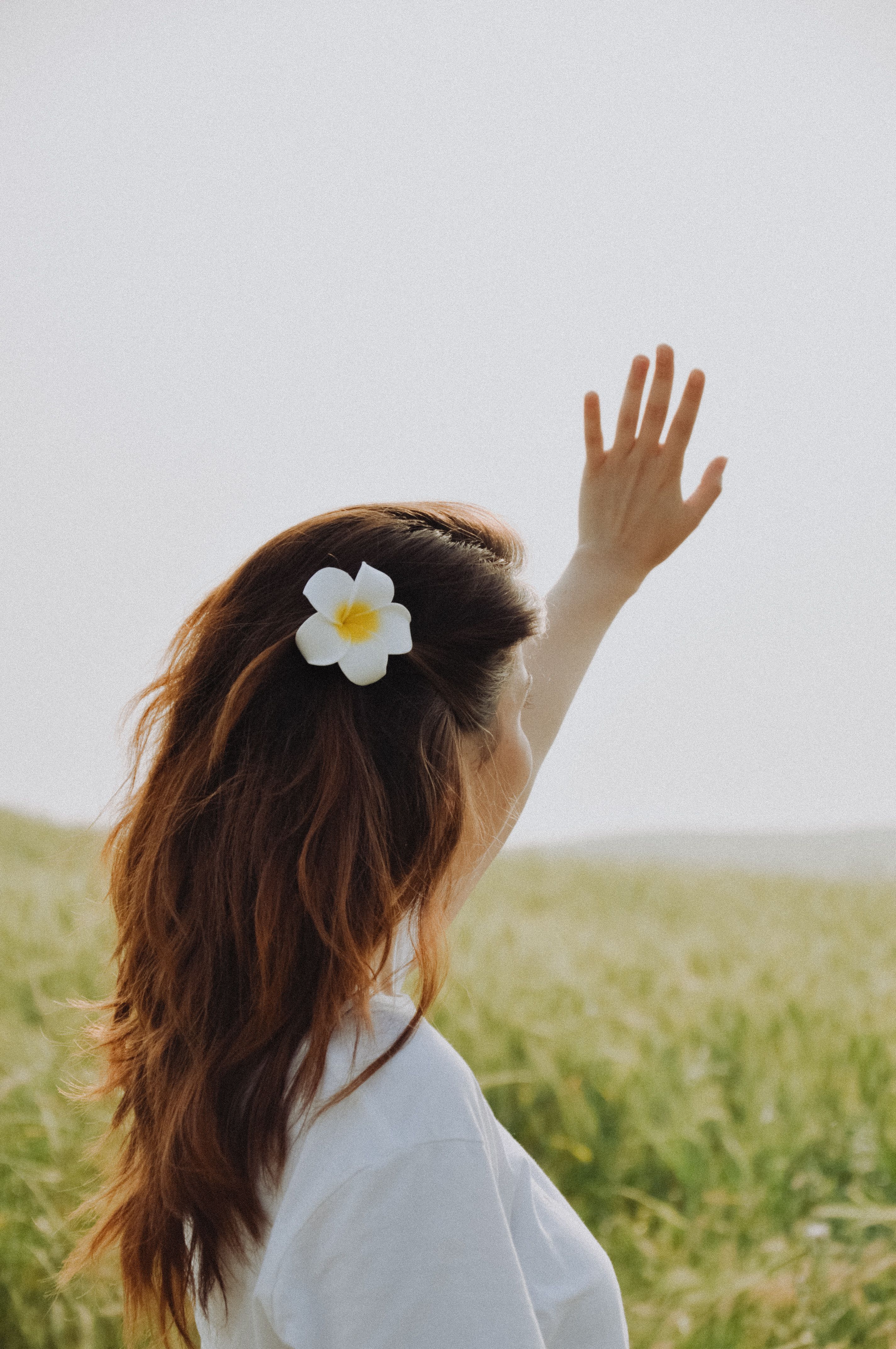 Woman with Flower in Hair Reaching to Sky Outdoors · Free Stock Photo