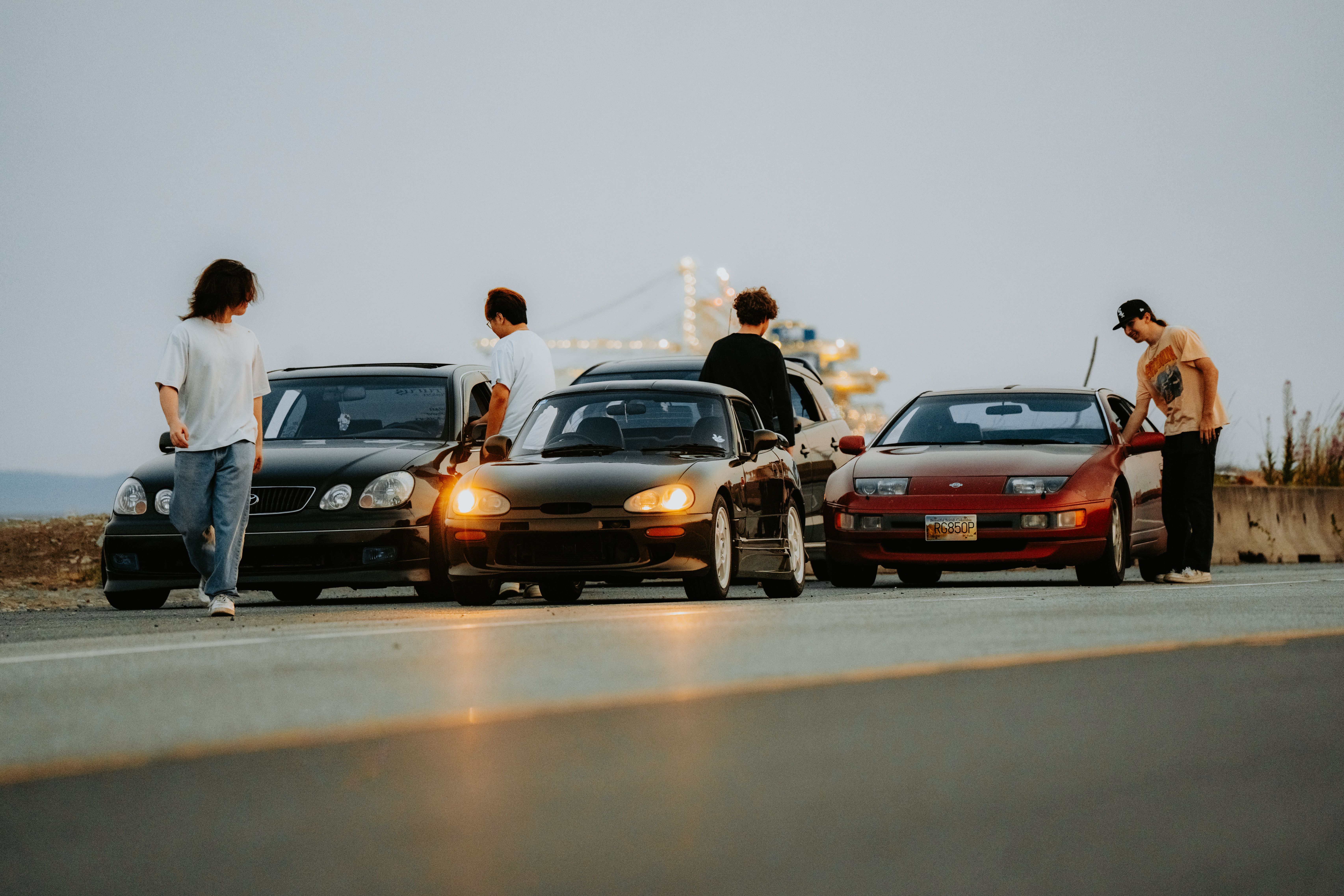 A group of people standing next to cars on a road · Free Stock Photo