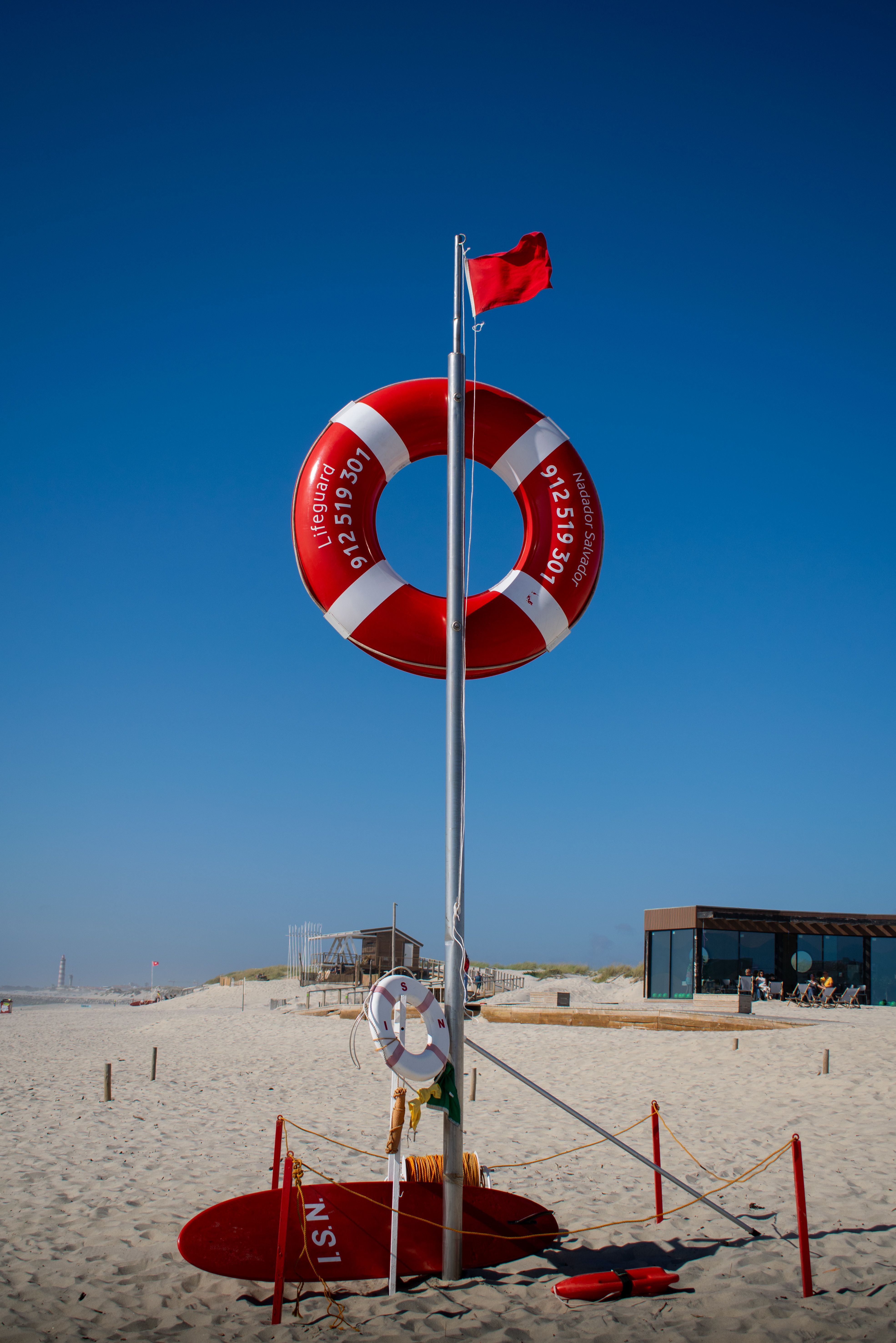 A life preserver on the beach with a red flag · Free Stock Photo