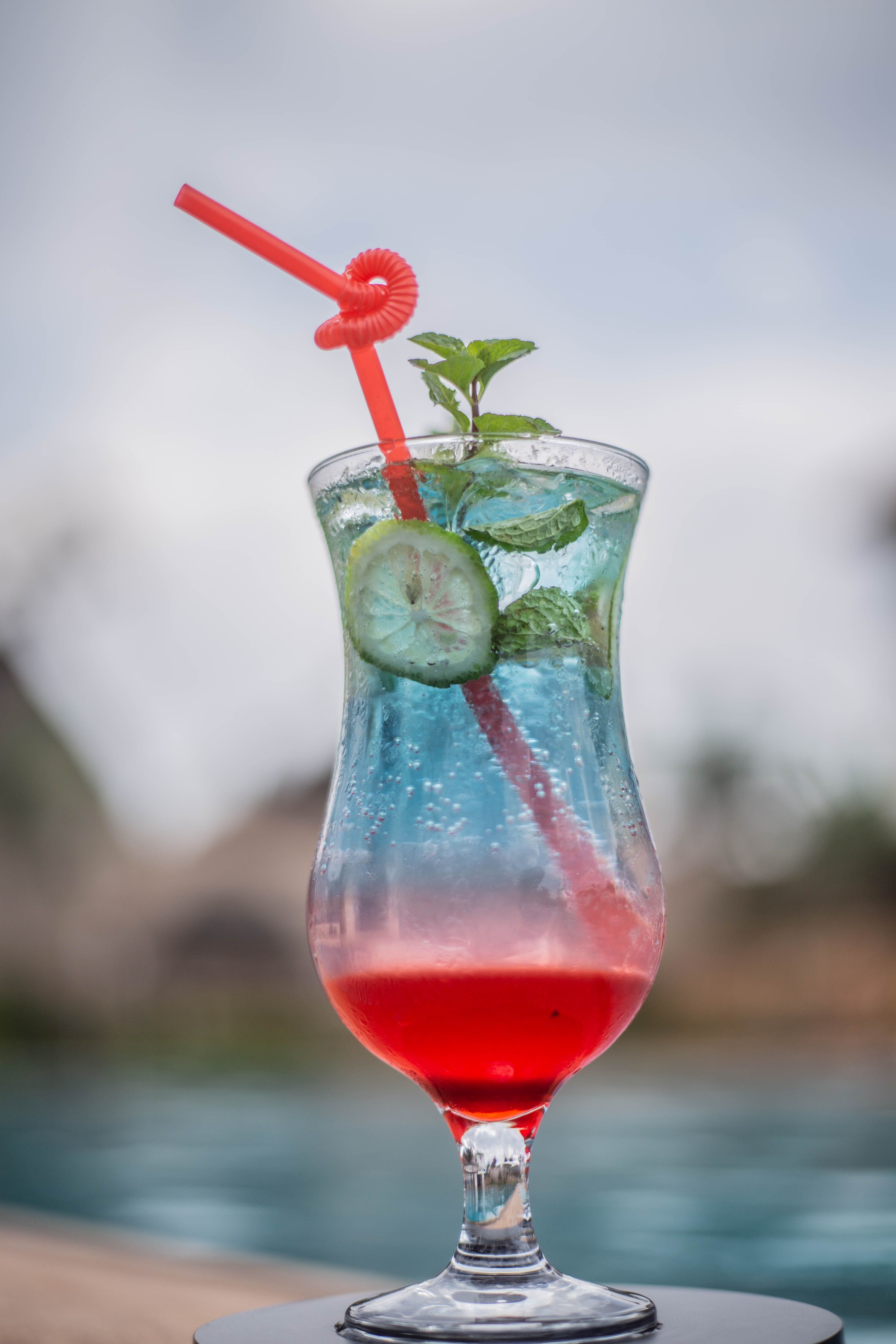 A cocktail with a straw and a red and blue drink · Free Stock Photo