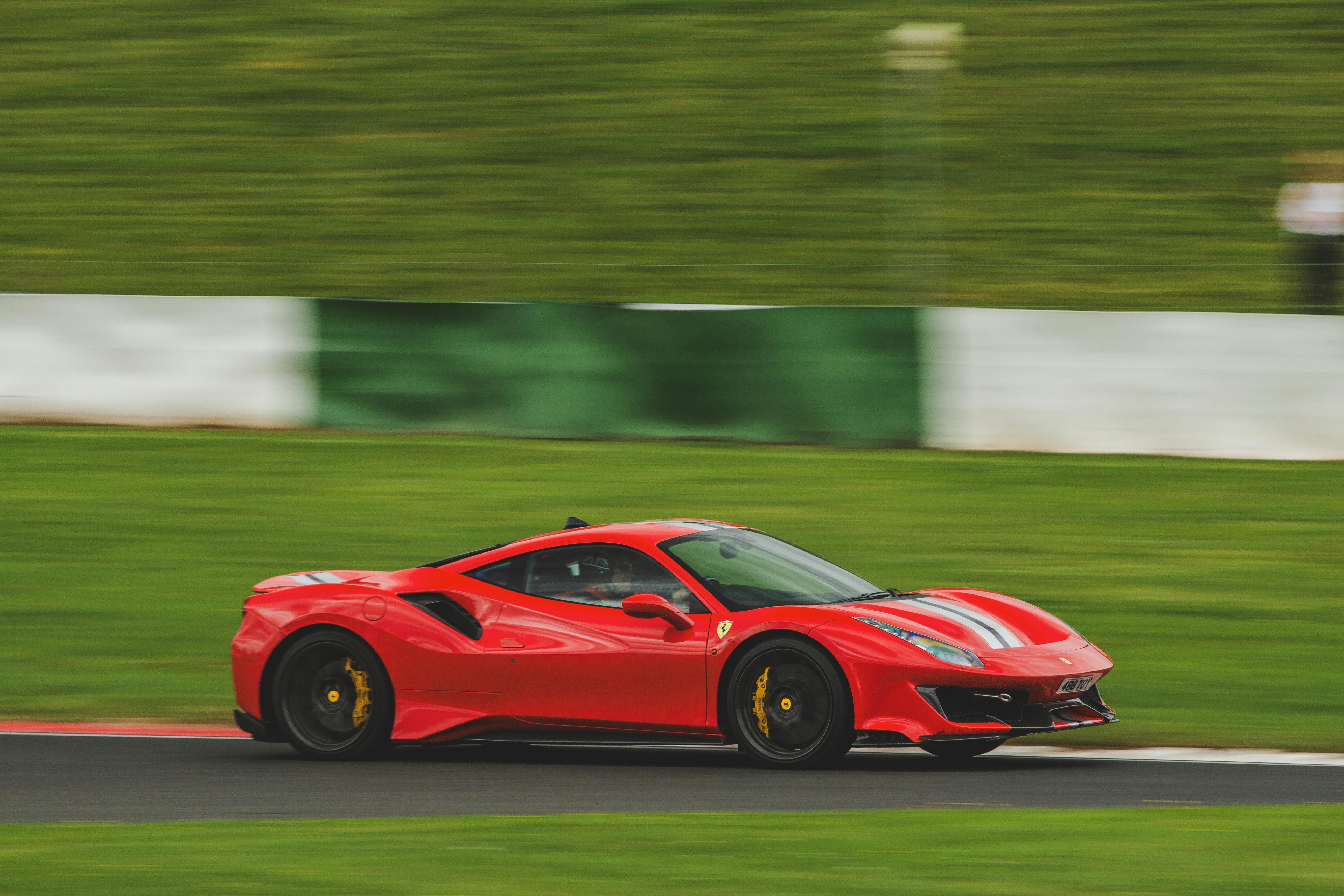 A red ferrari sports car driving on a track · Free Stock Photo